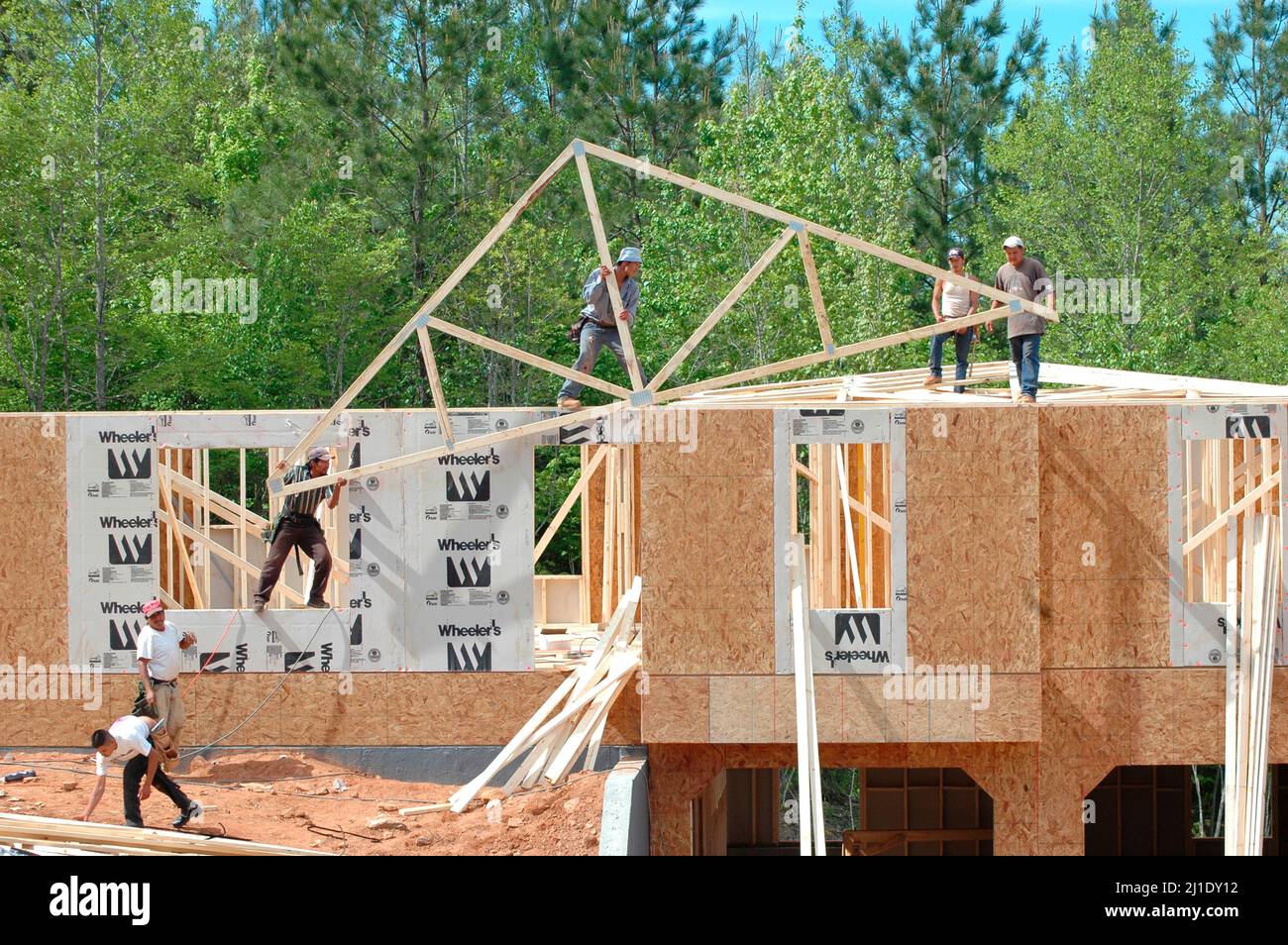 Measuring and cutting wood frame home construction by workers, stick ...