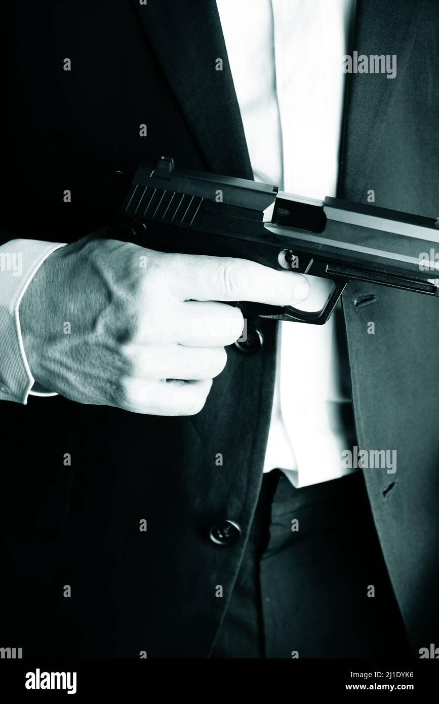 Retro secret agent with pistol revolver gun in hand in vintage crime ...