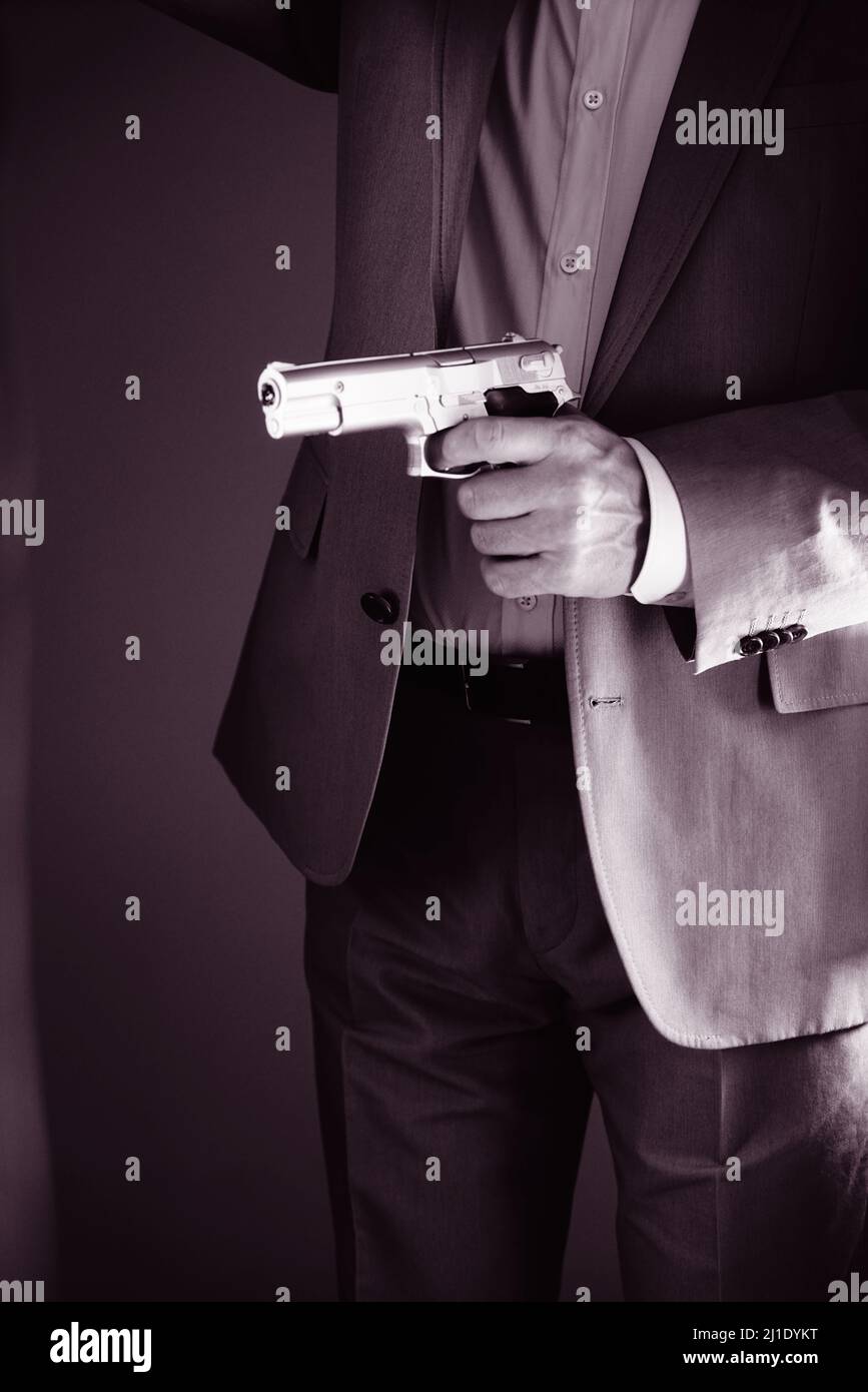 Retro secret agent with pistol revolver gun in hand in vintage crime ...