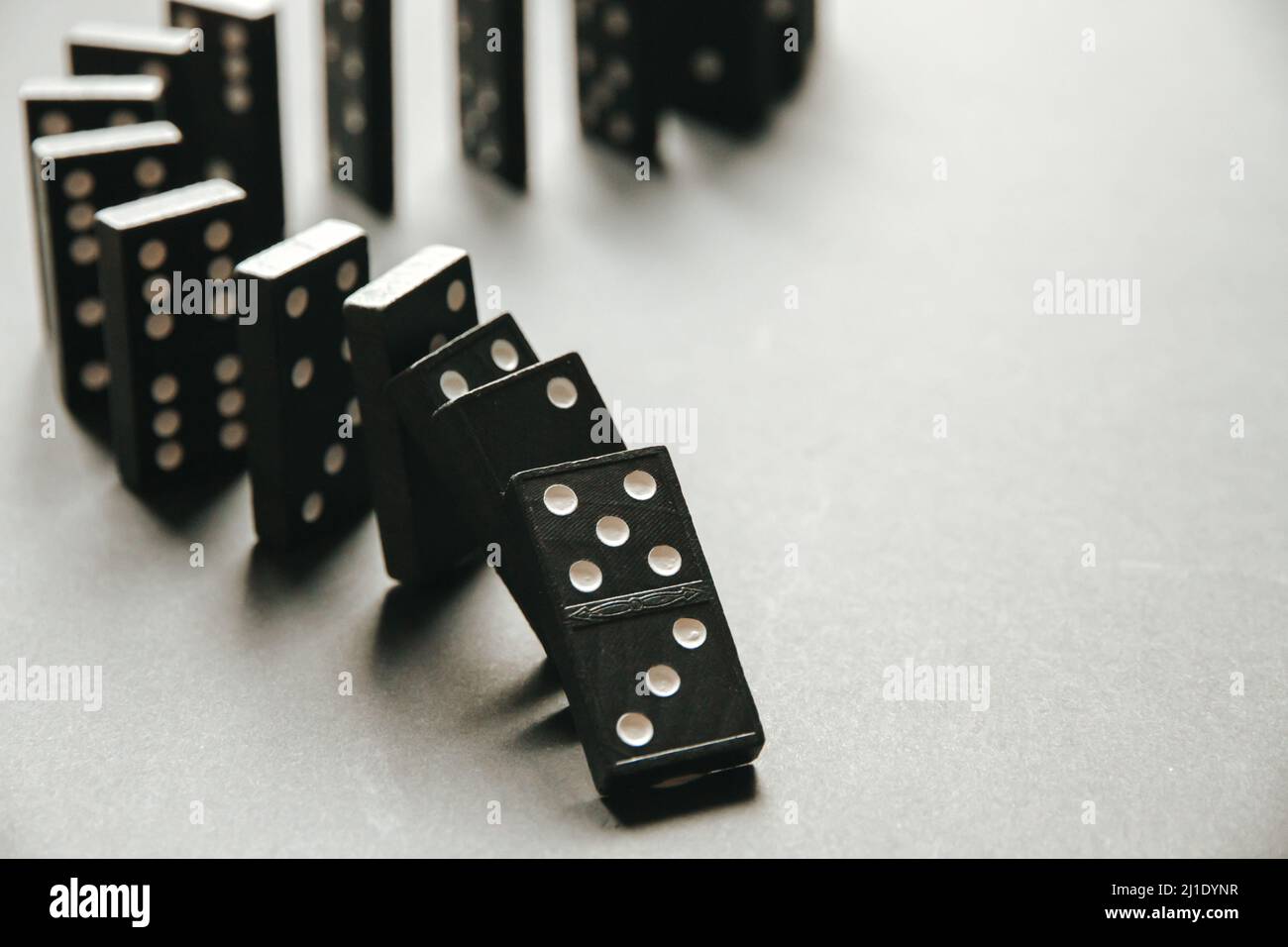 Black dominoes chain on a white table background. Domino effect concept ...