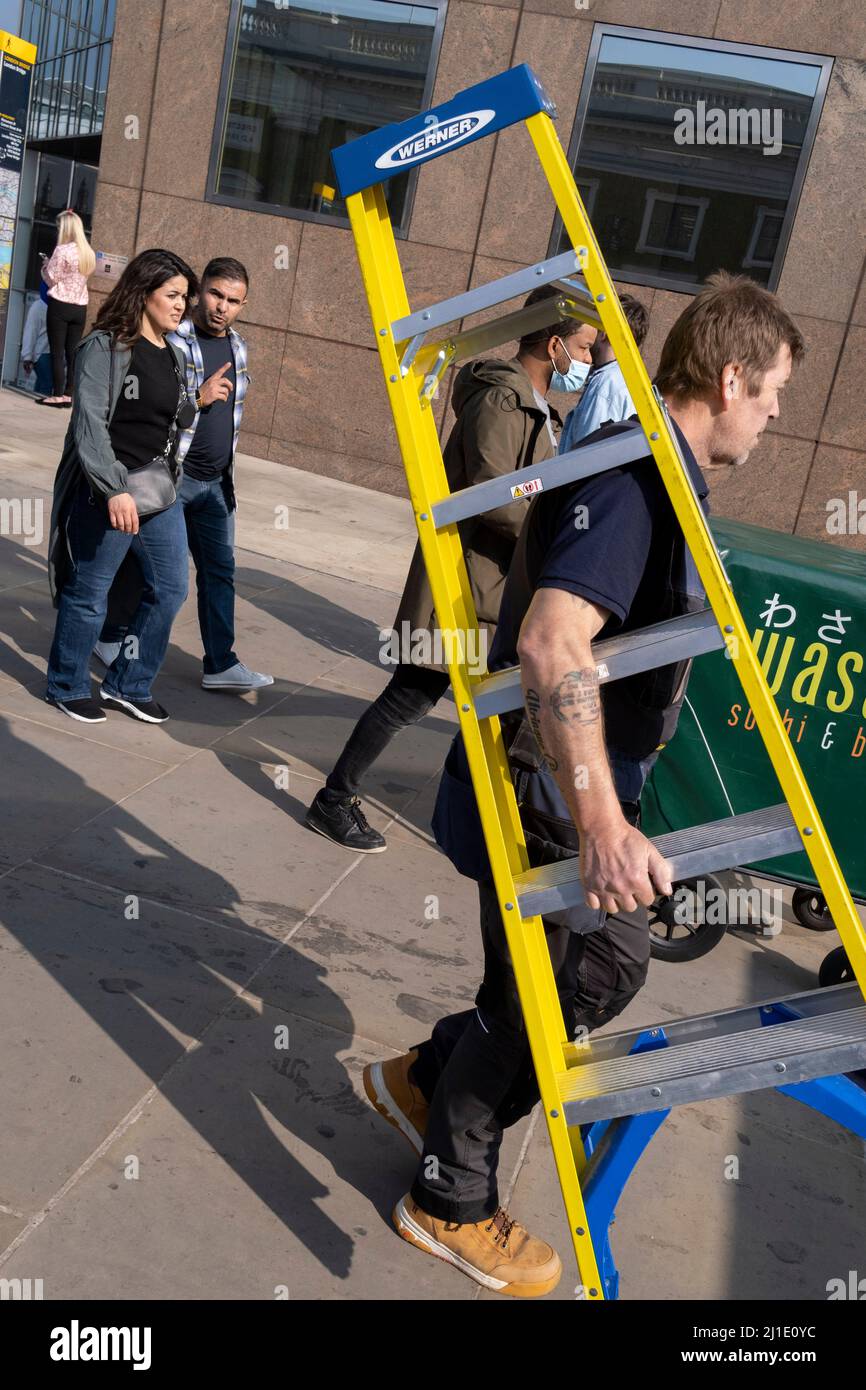 A workman carries aluminium ladders over London Bridge, on 24th March ...