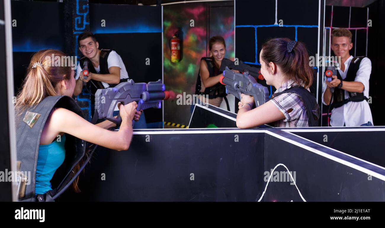 Two teams of laser tag game smiling girls and guys playing opposite ...