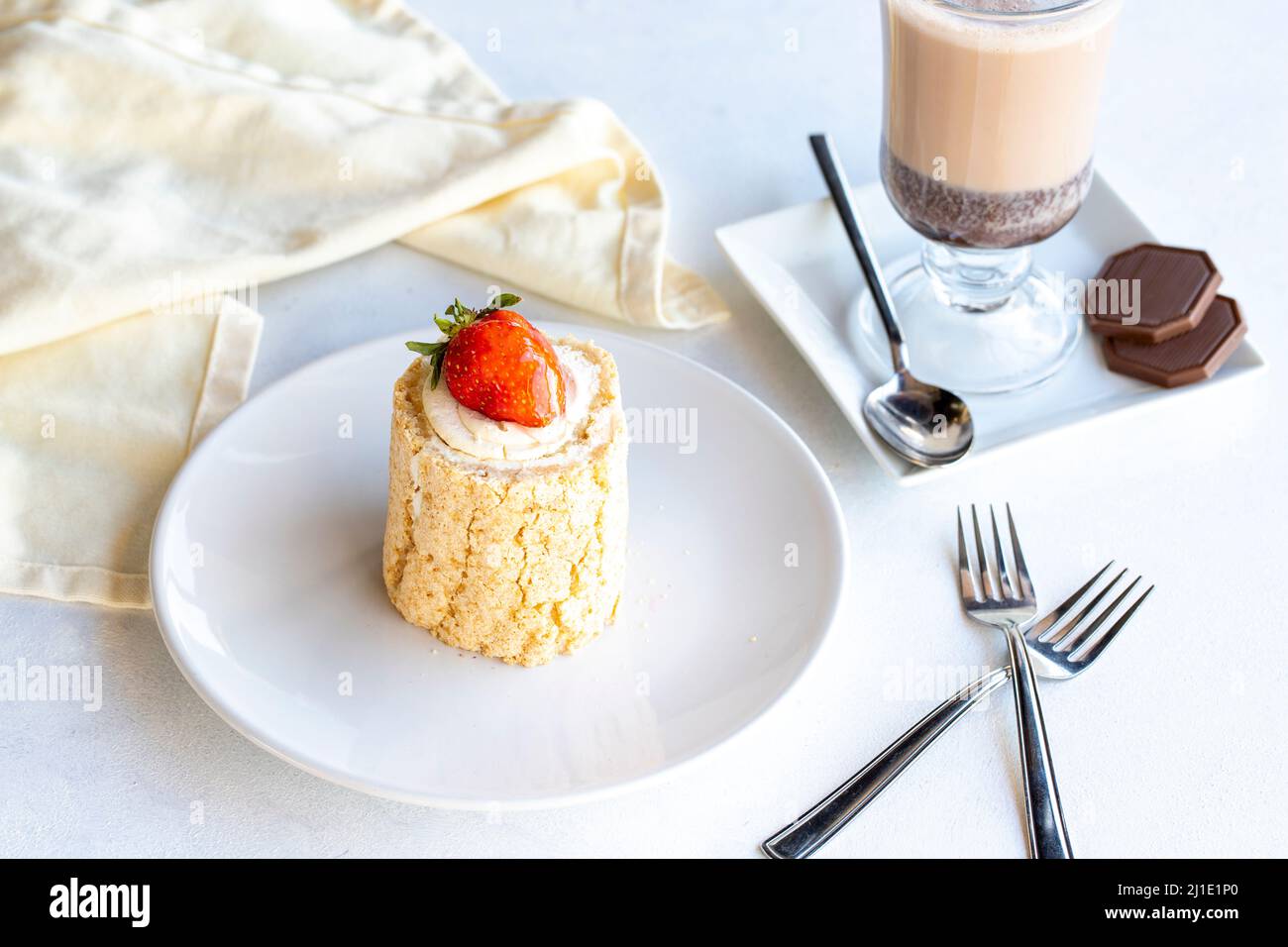 Strawberry log cake on a white background. With hot chocolate on the ...