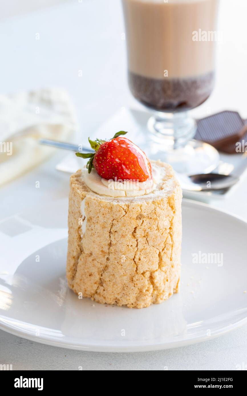 Strawberry log cake on a white background. With hot chocolate on the ...