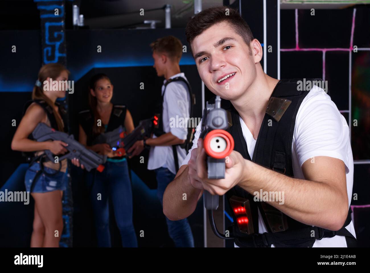 Excited guy with laser pistol while playing lasertag with his friends ...