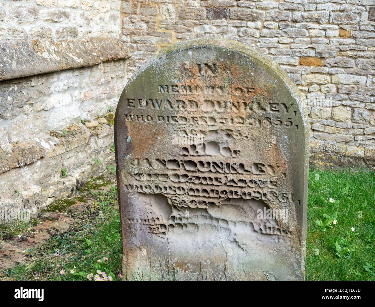 Heavily eroded gravestone in the churchyard of St Peter and St Paul ...