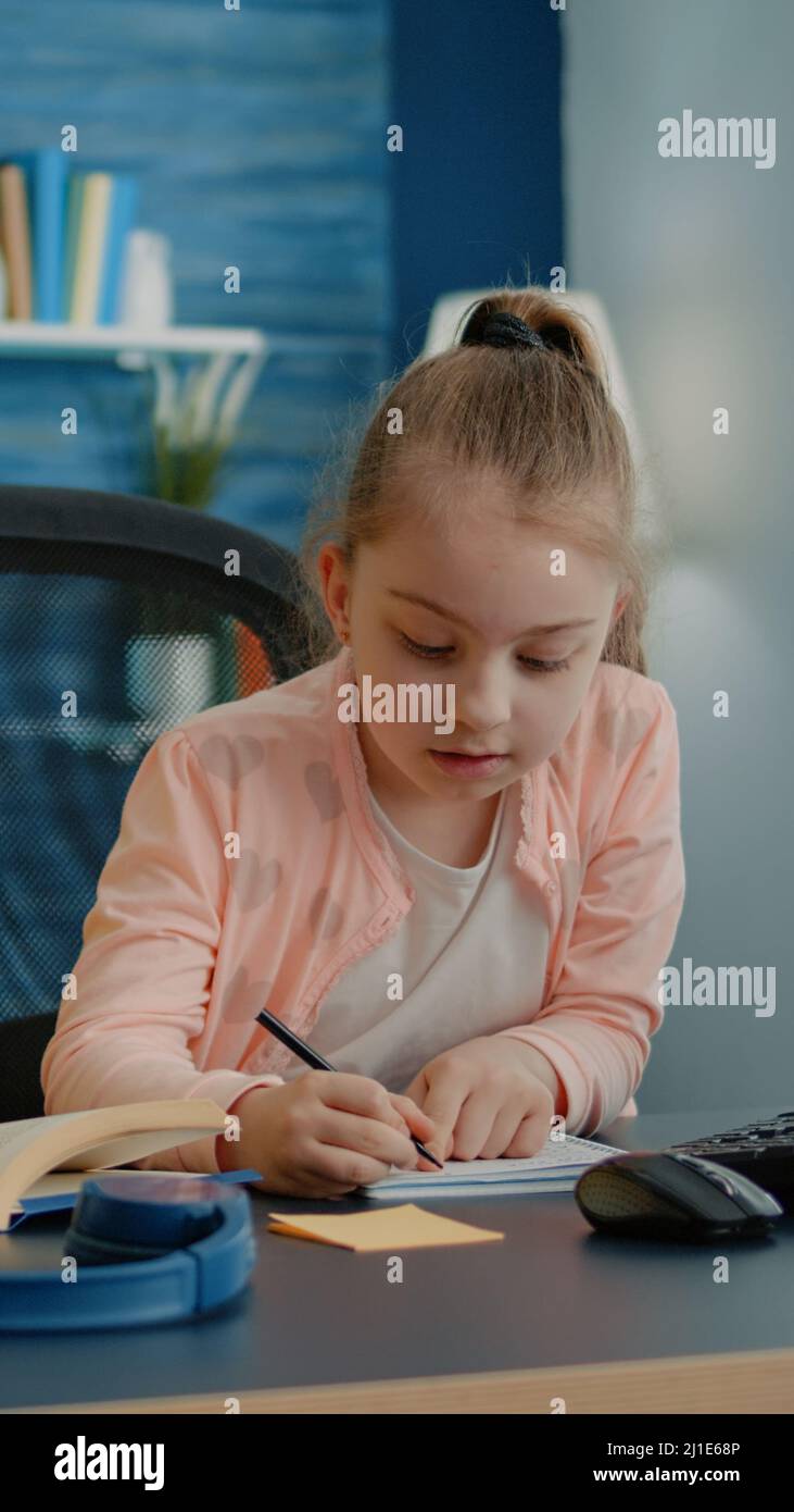 Little girl writing on notebook with pen while mother giving assistance ...