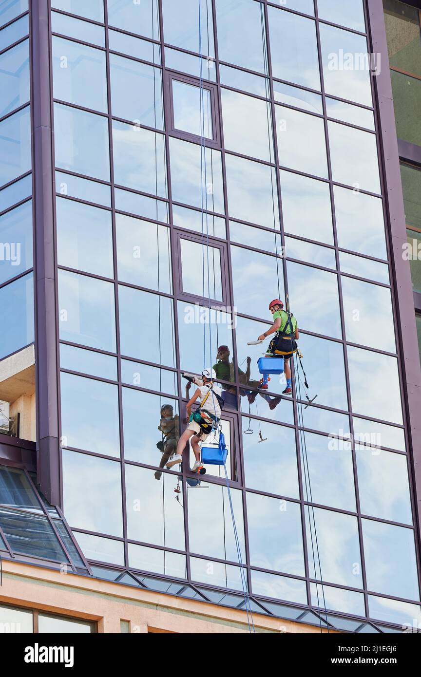 Industrial mountaineering workers washing glass windows of high-rise ...