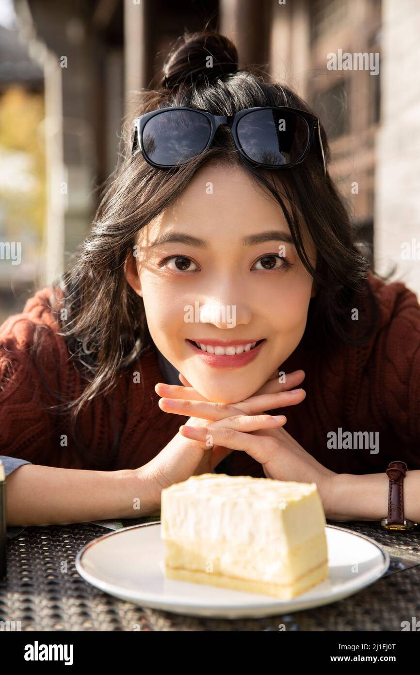 Chinese college student enjoying afternoon tea in sidewalk cafe - stock ...
