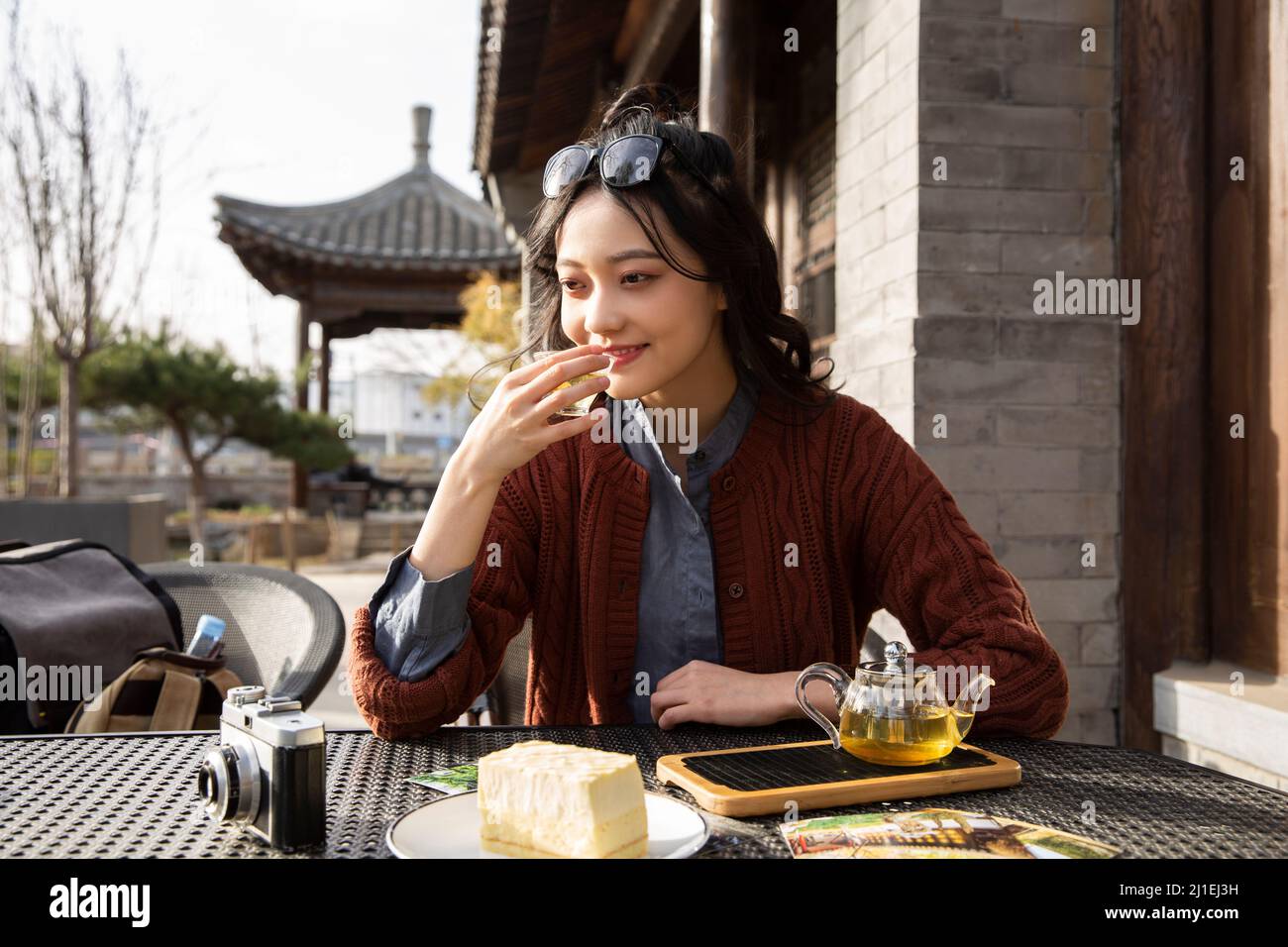 Chinese college student enjoying afternoon tea in sidewalk cafe - stock ...