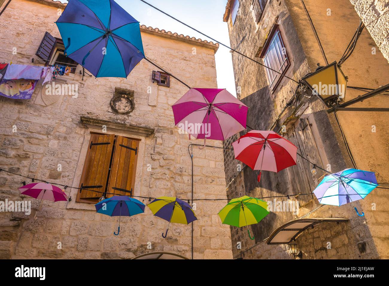 Colorful umbrellas hanging in a stone street in the historic center of ...