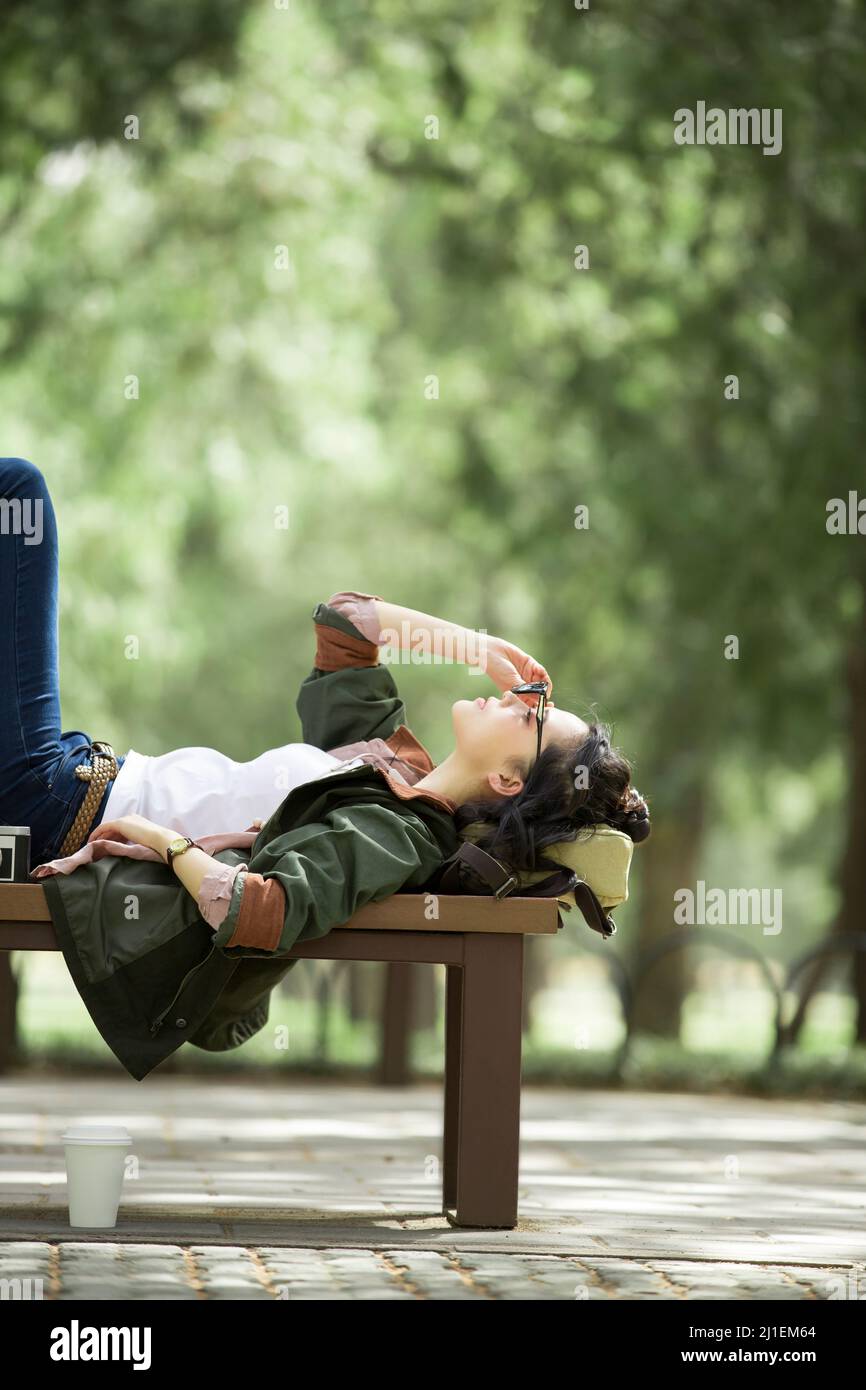 Young female photographer lying and resting on bench - stock photo ...