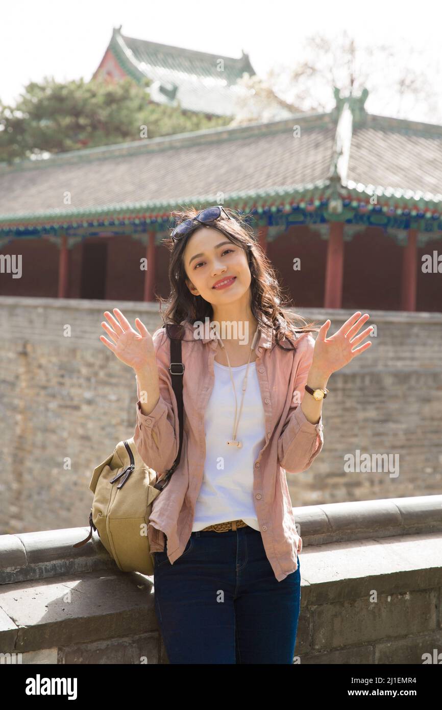 Young female tourist greeting camera by the ancient Chinese promenade ...