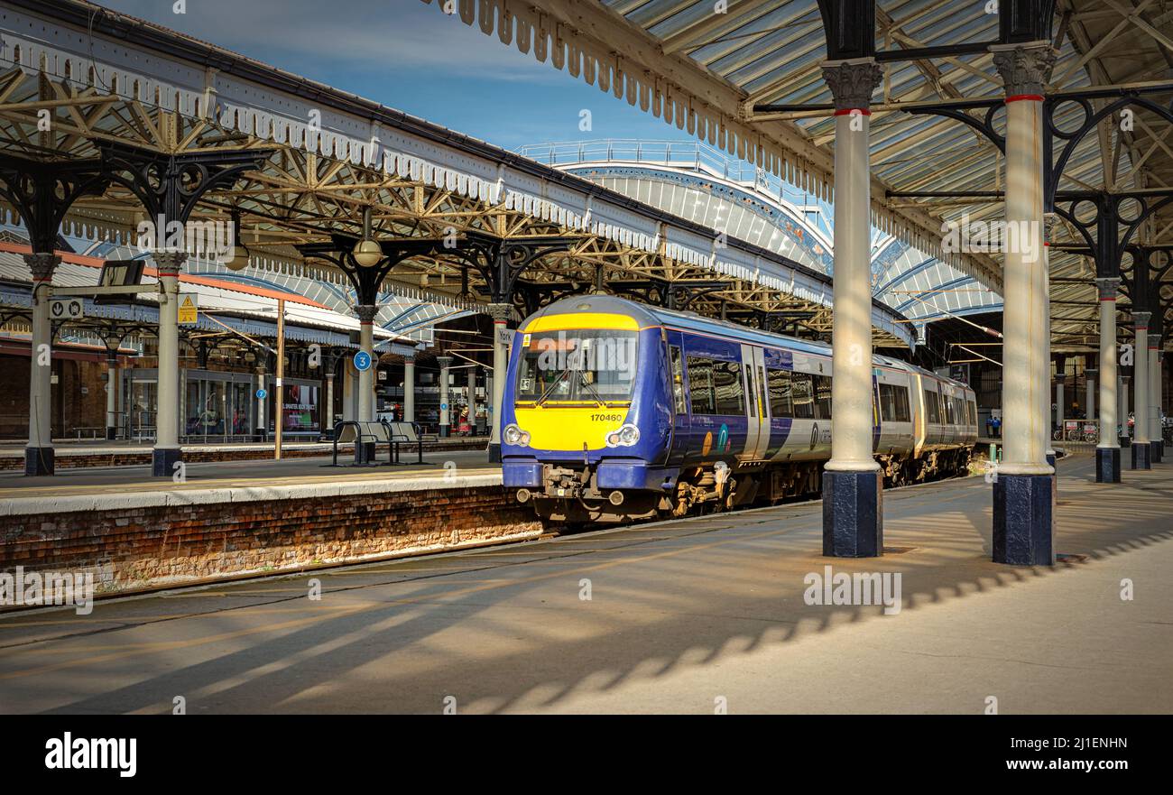 Railway station platform with a train alongside. Overhead is an ...