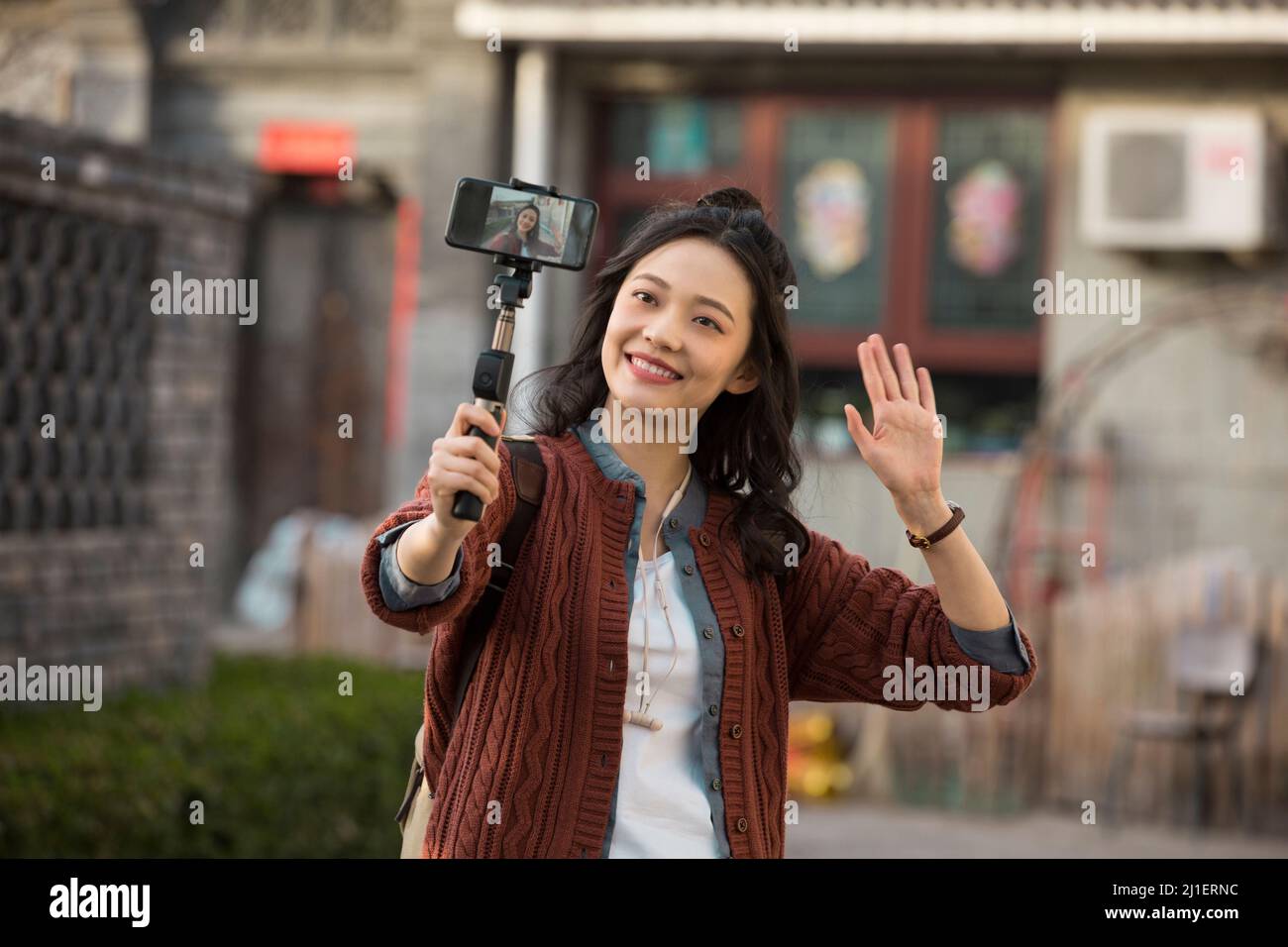 Smiling young Chinese lady greeting as living on her mobile phone ...