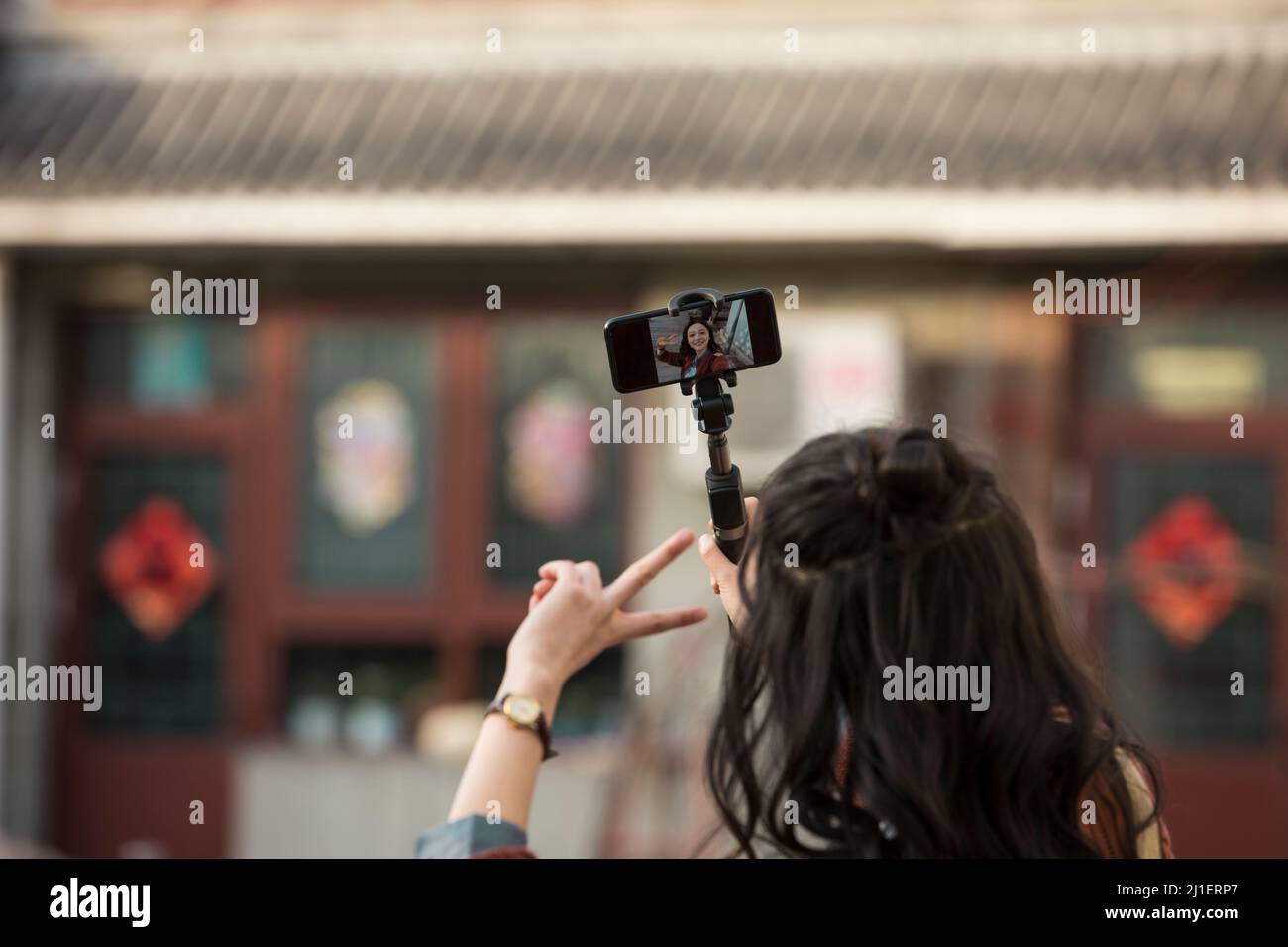 Back view of long curly hair young Chinese lady taking selfies with ...