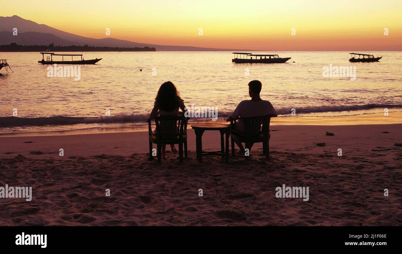 a photo of couple on the beach watching sunset Stock Photo - Alamy