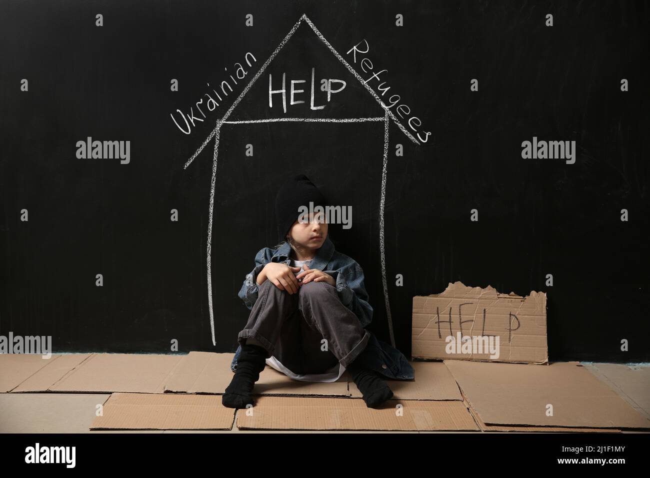Homeless little girl sitting on floor near dark wall with drawn house ...
