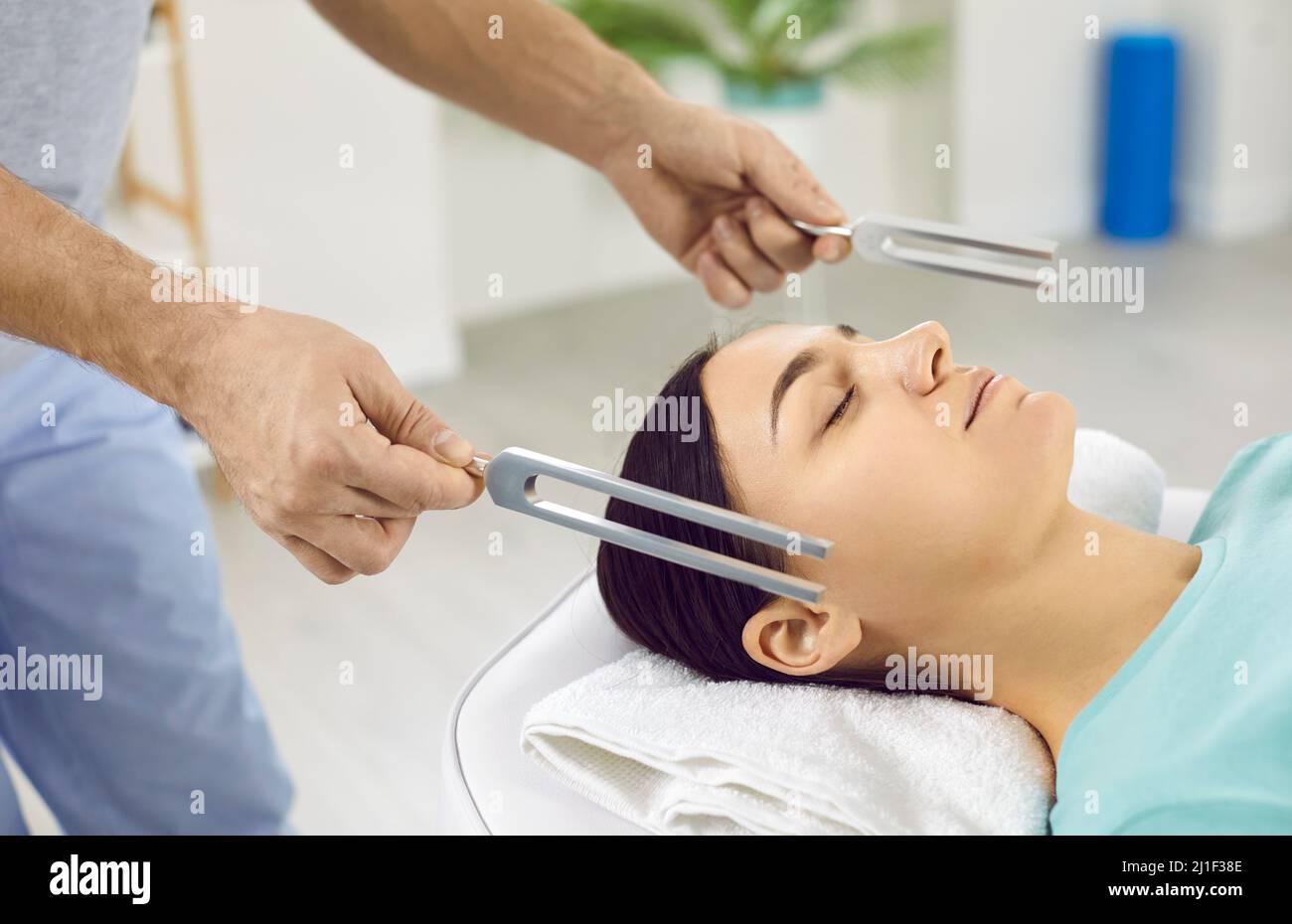 Holistic doctor healing young patient with help of tuning forks and ...