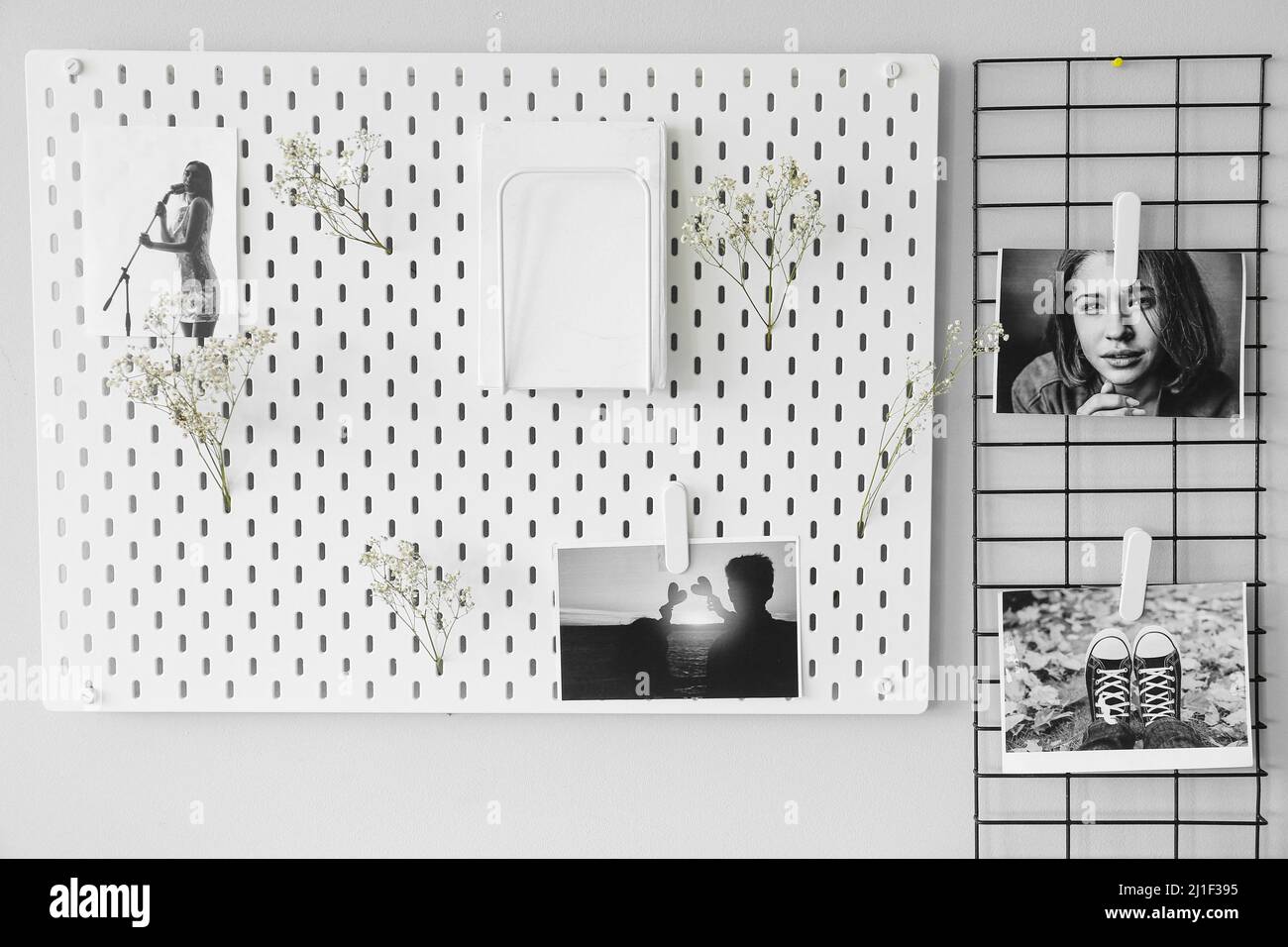 Stylish peg board with photos and book hanging on light grey wall Stock ...