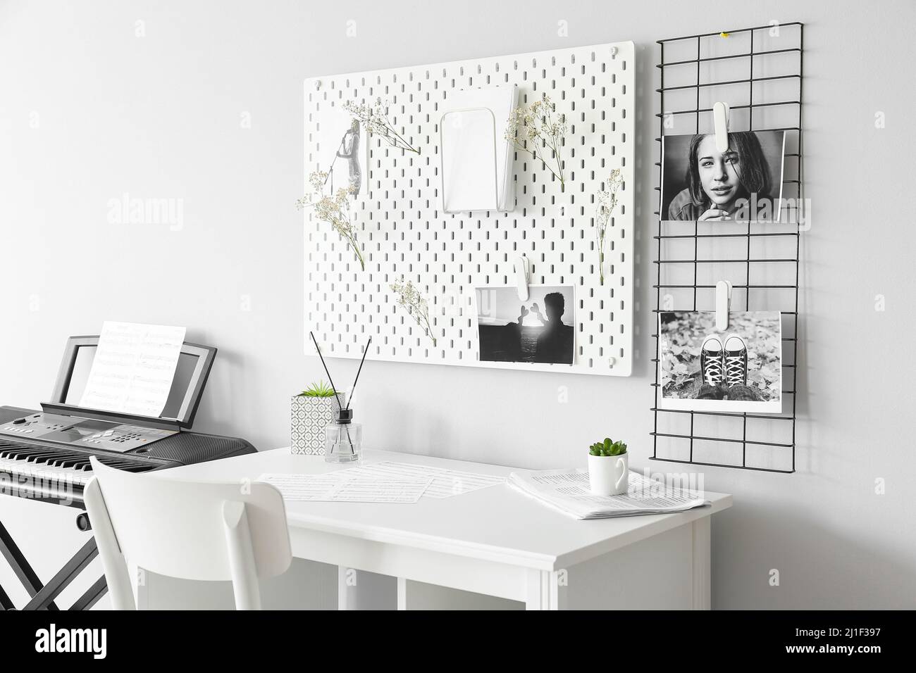 Modern synthesizer and workplace with peg board on wall in room Stock ...