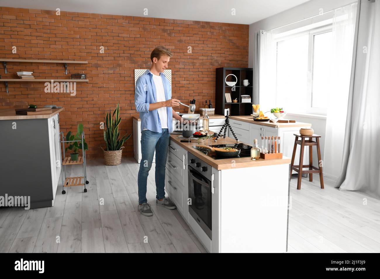 Young man pouring soup into bowl in kitchen Stock Photo - Alamy