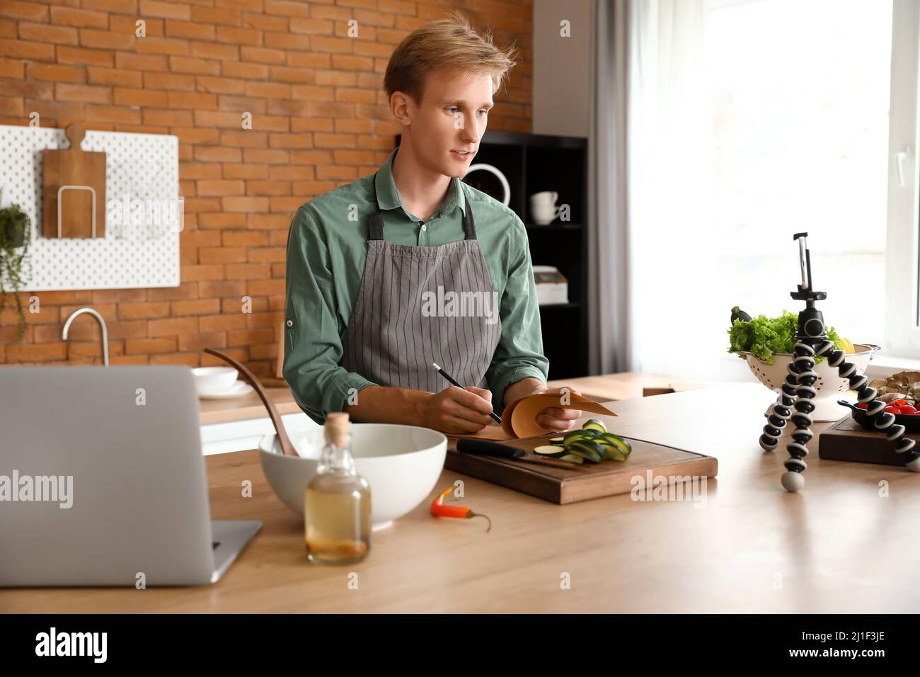 Young man making notes from cooking video tutorial in kitchen Stock ...