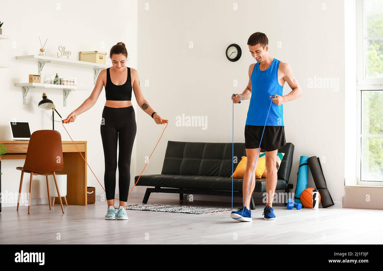 Sporty young couple jumping rope at home Stock Photo - Alamy