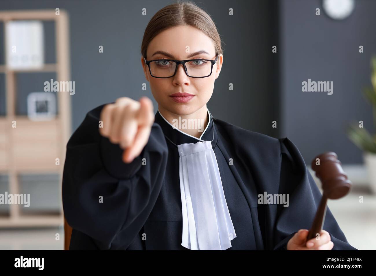 Young female judge with gavel pointing at viewer in courtroom Stock ...