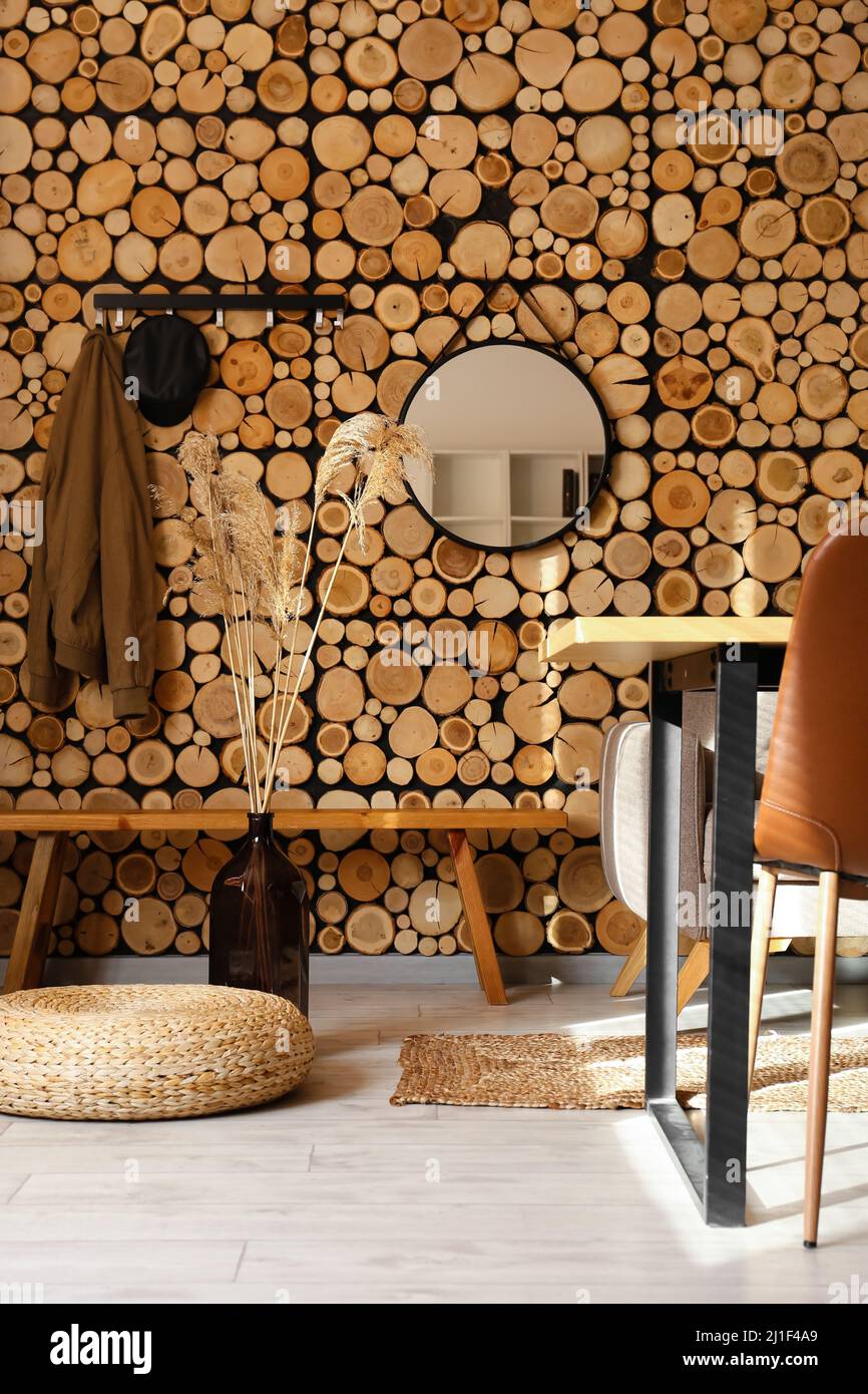 Interior of stylish dining room with table, clothes rack and bench ...