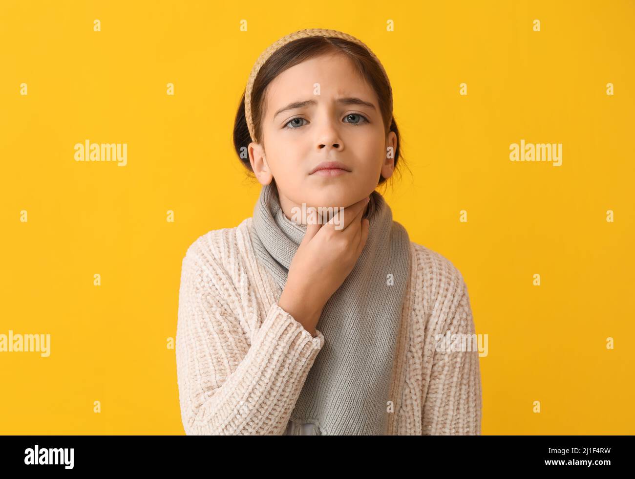 Sad little girl suffering from sore throat on yellow background Stock ...
