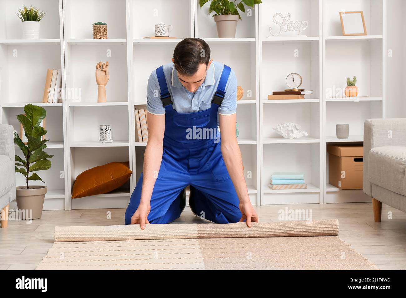 Male worker rolling stylish carpet in room Stock Photo - Alamy