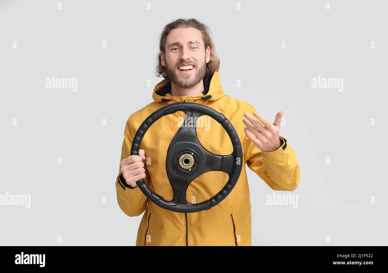 Handsome man with steering wheel on grey background Stock Photo - Alamy