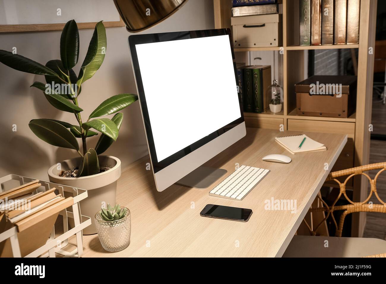 Workplace with modern computer, mobile phone and houseplant in dark ...