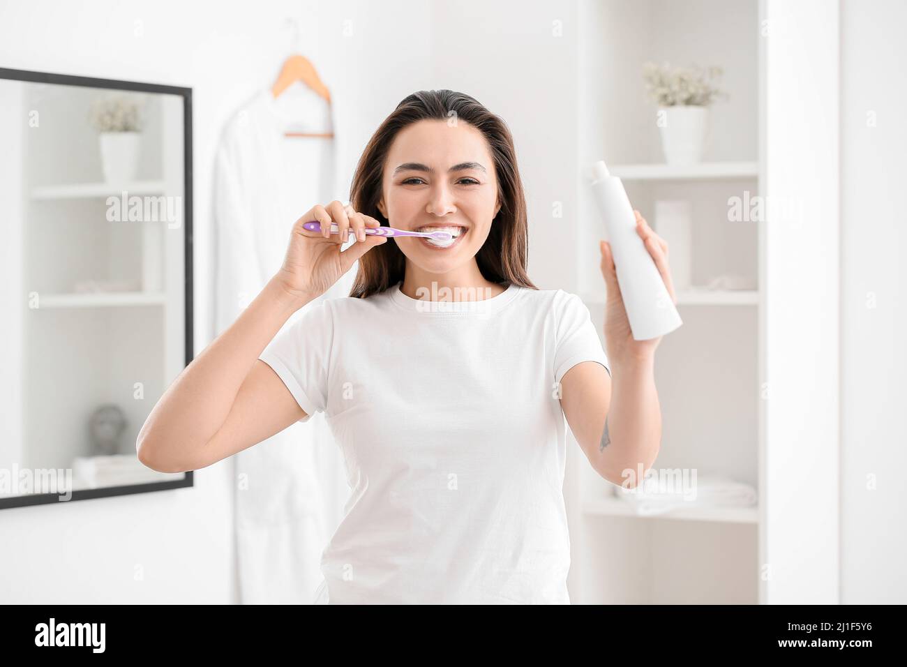 Young woman with paste brushing teeth in bathroom Stock Photo - Alamy