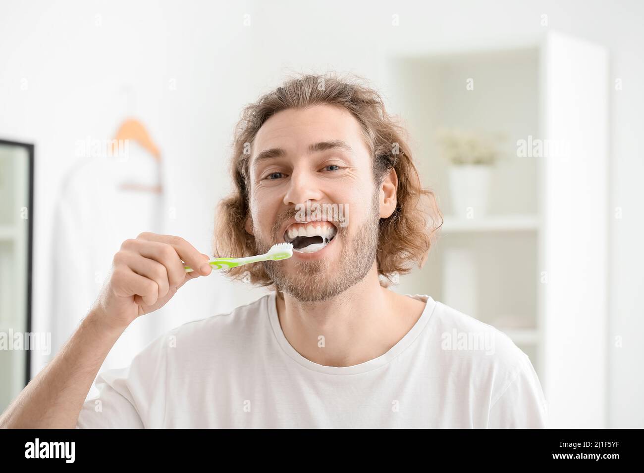 Handsome young man brushing teeth in bathroom, closeup Stock Photo - Alamy