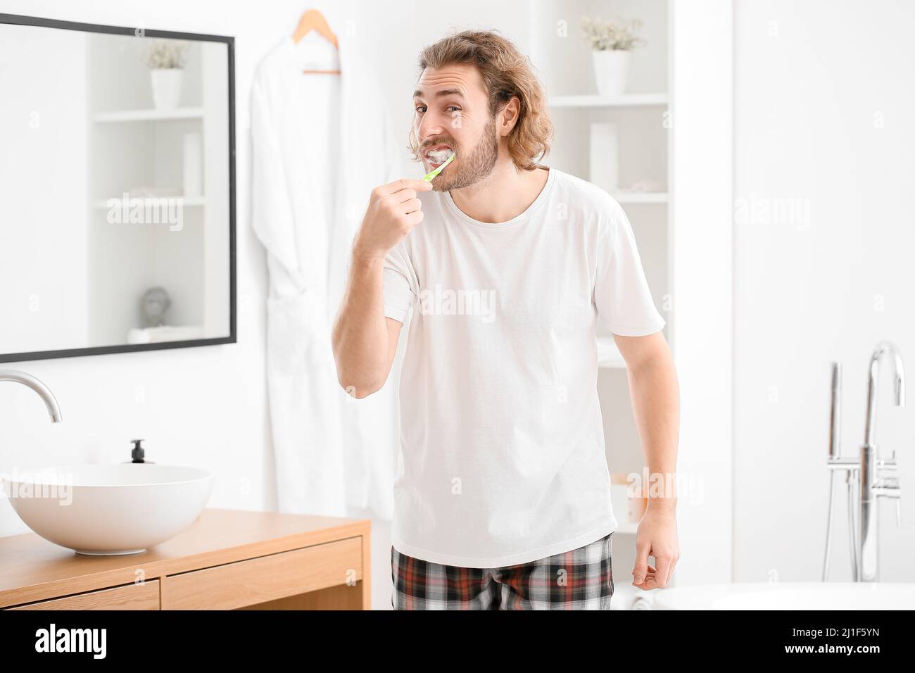 Handsome young man brushing teeth in bathroom Stock Photo - Alamy