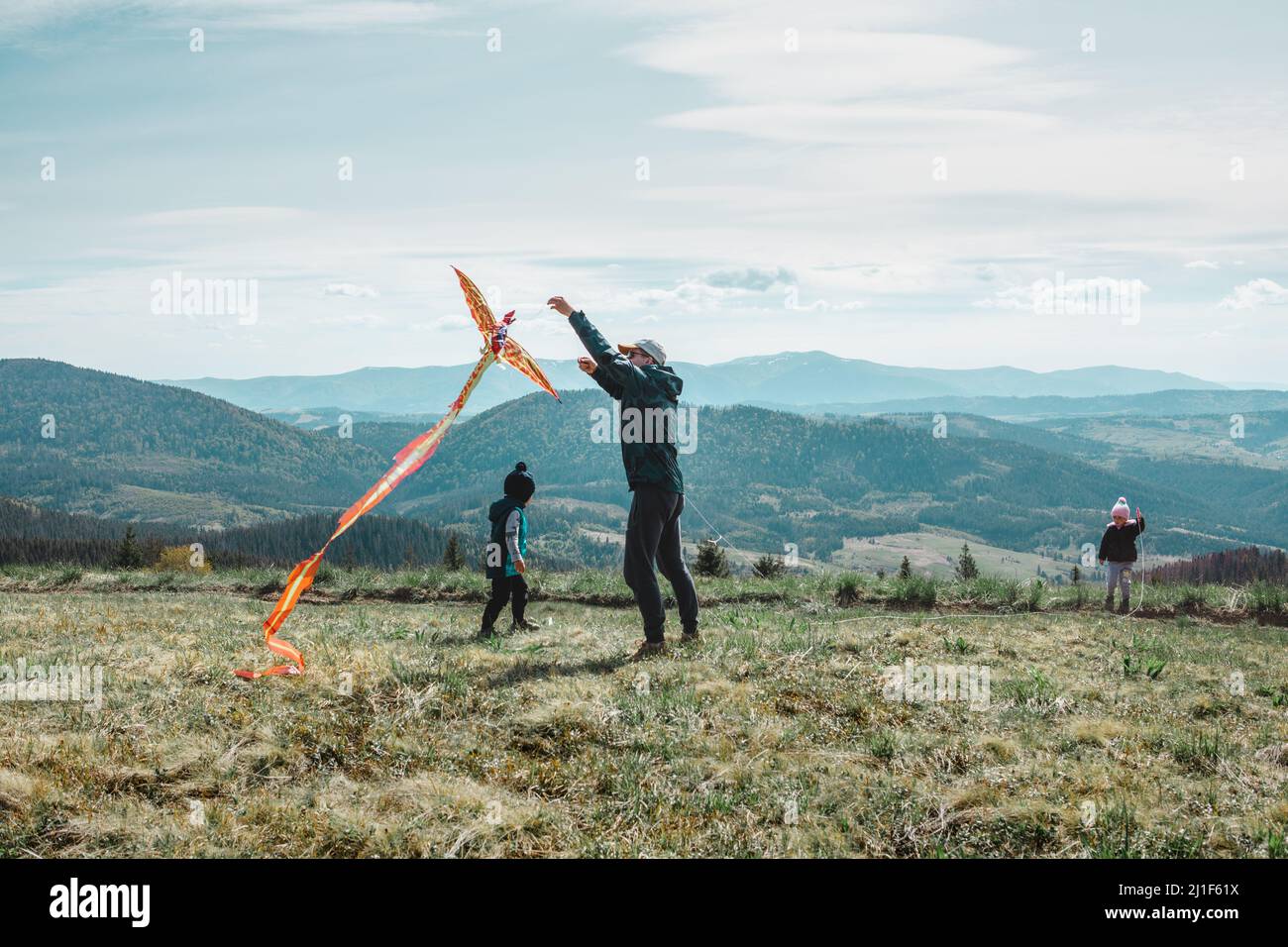man with kids playing outdoors with kite catching wind. having fun ...