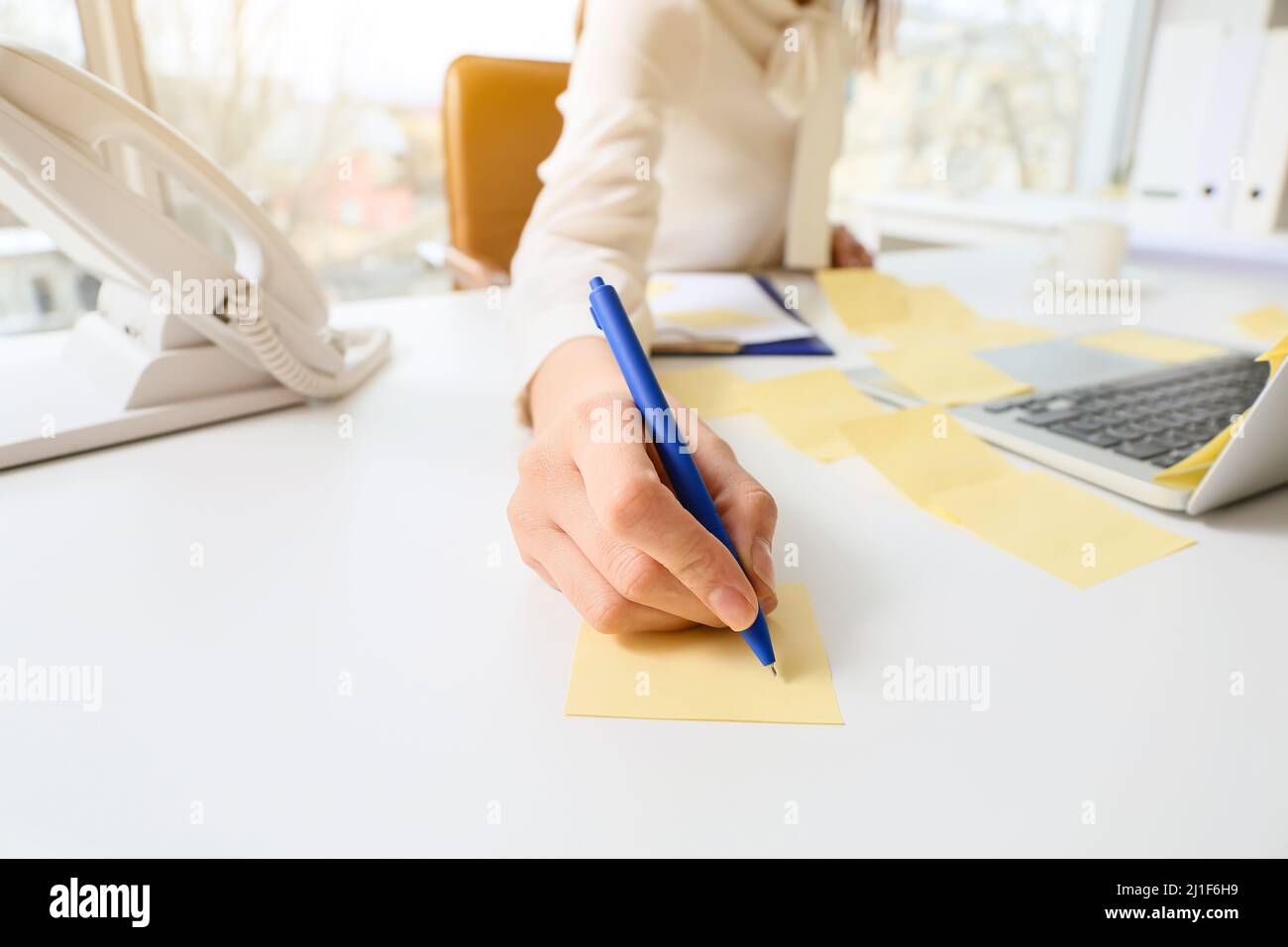Young manager writing on sticky note paper at her workplace Stock Photo ...
