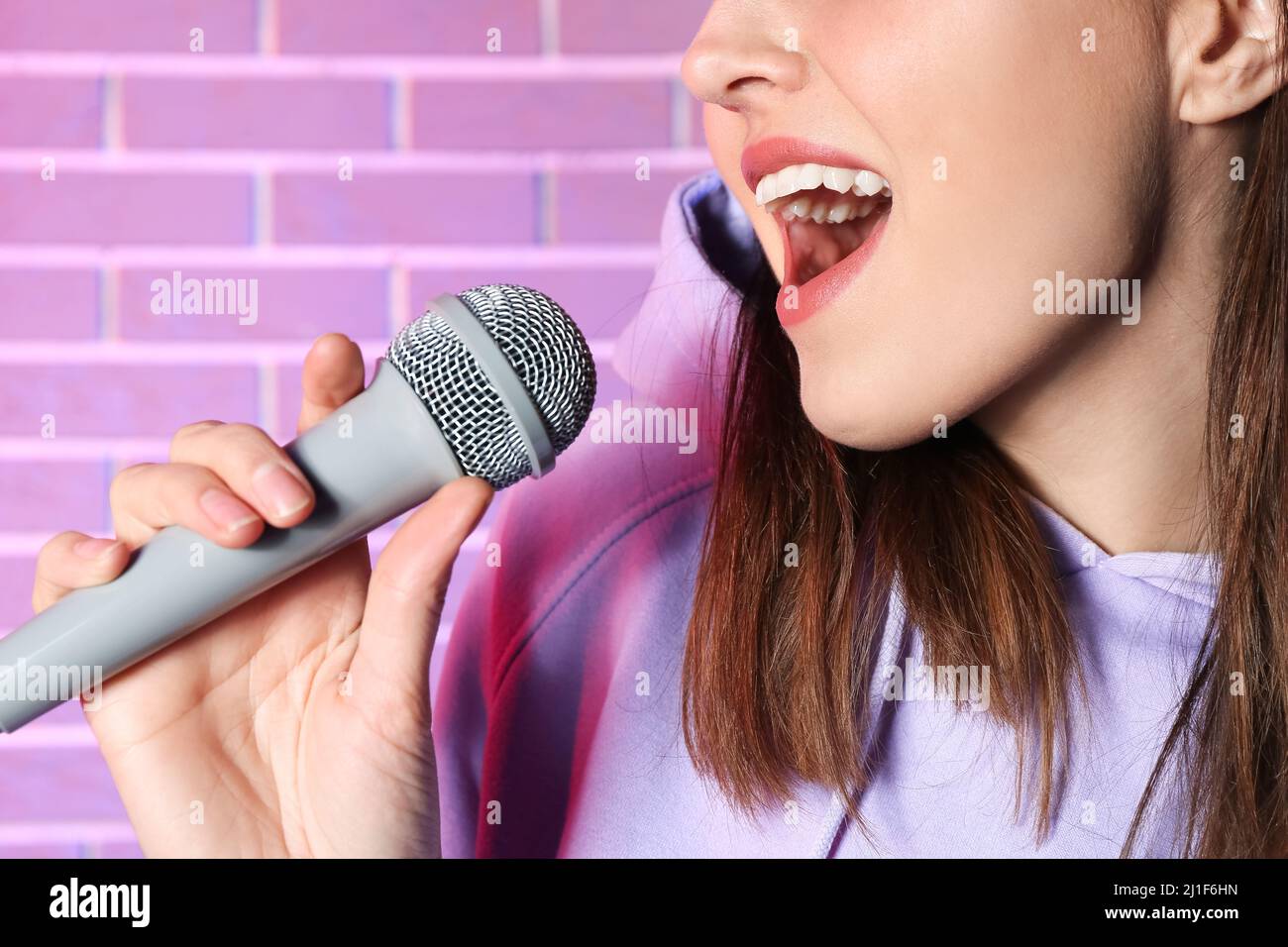 Cool young woman singing on color brick background, closeup Stock Photo ...