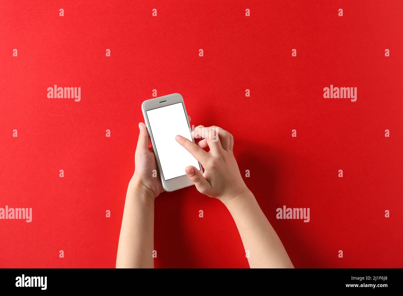 Child using modern mobile phone on red background Stock Photo - Alamy