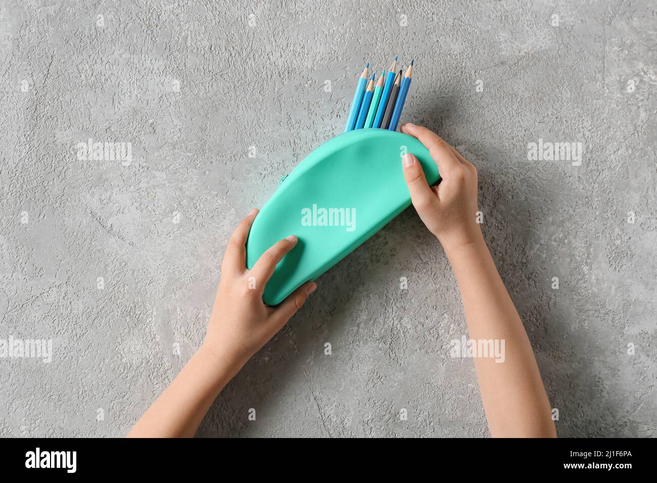 Child holding pencil case with color pencils on light background Stock ...
