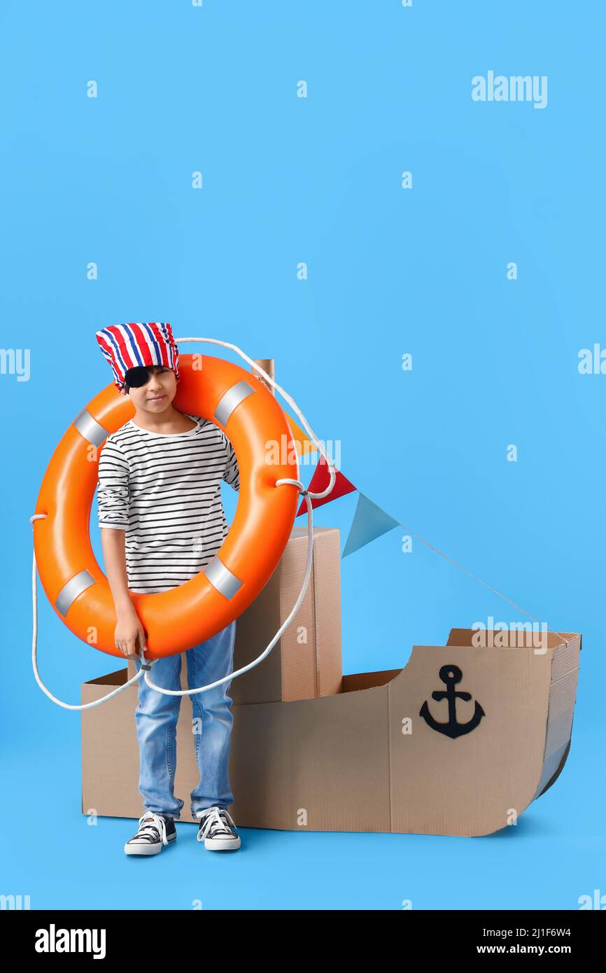 Cute little boy playing with cardboard ship on blue background Stock ...