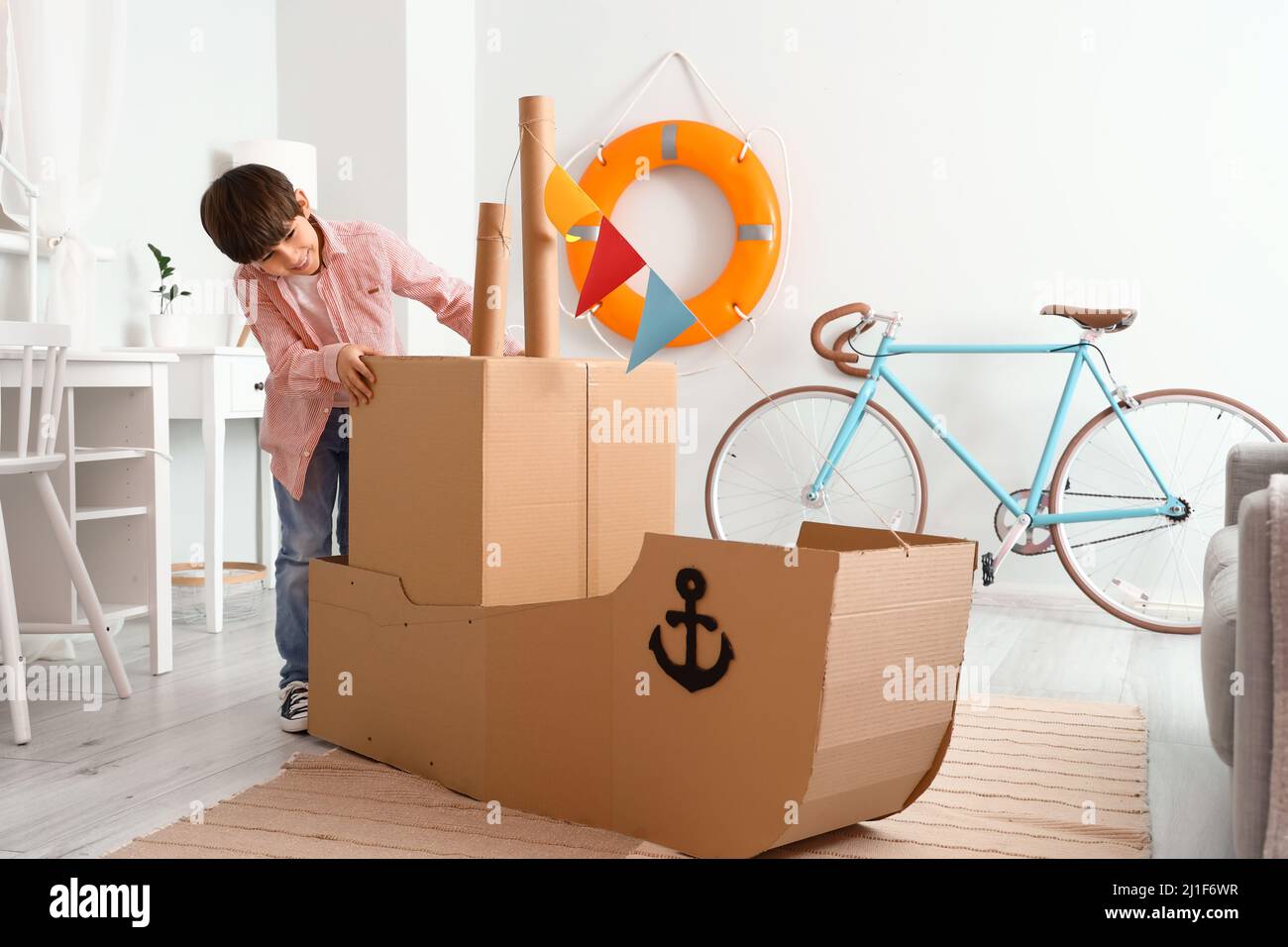 Cute little boy playing with cardboard ship at home Stock Photo - Alamy