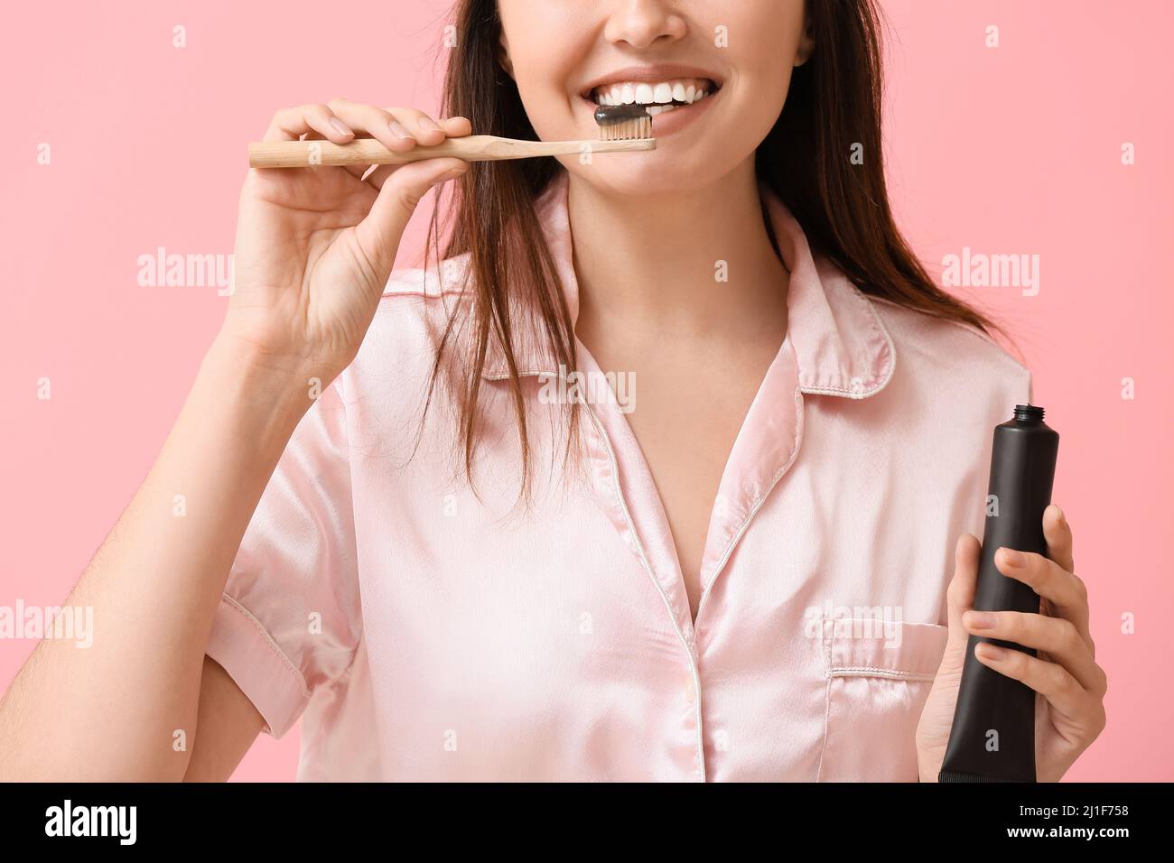 Beautiful young woman brushing teeth with activated charcoal tooth ...