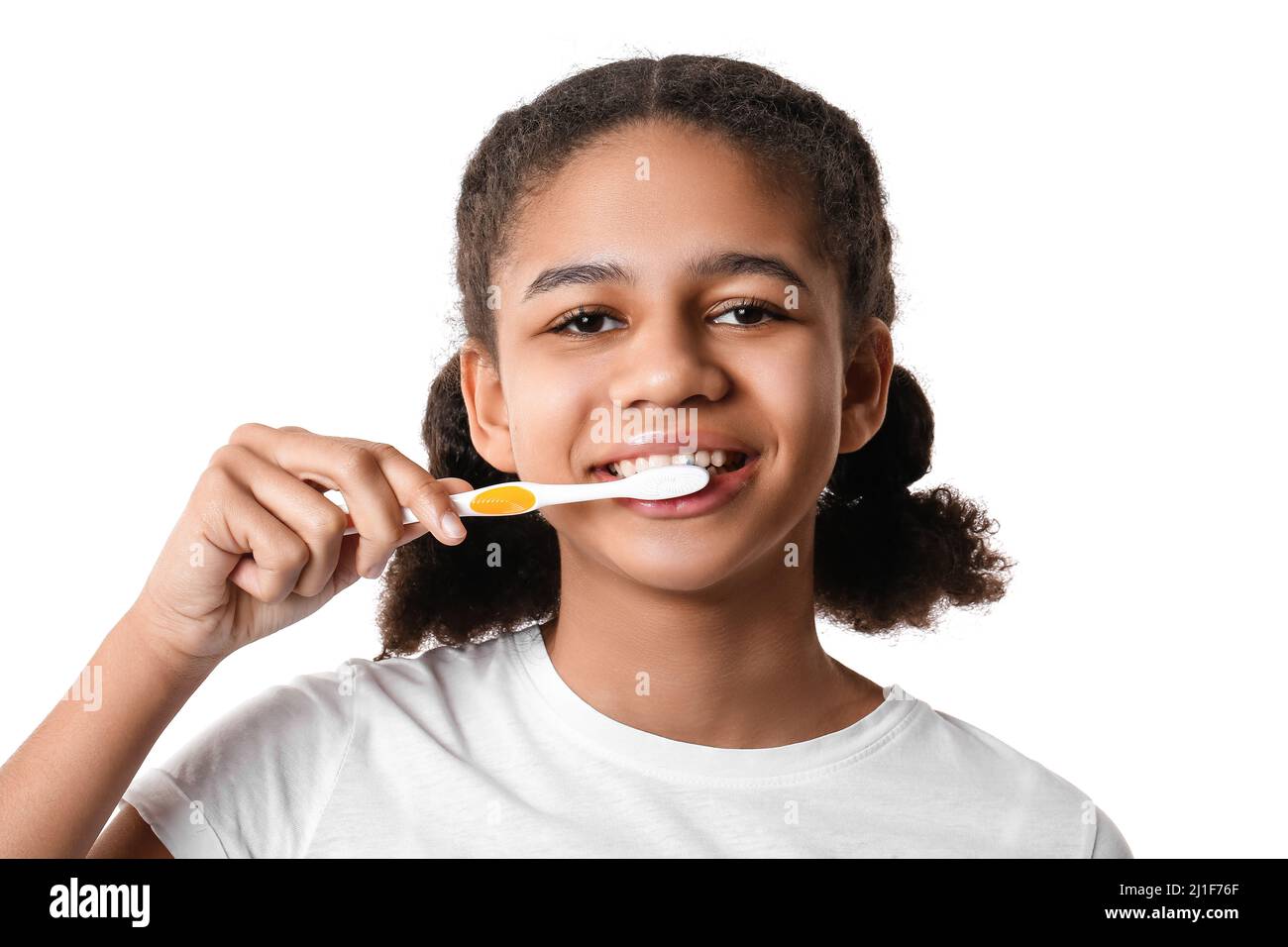 African-American teenage girl brushing her teeth on white background ...