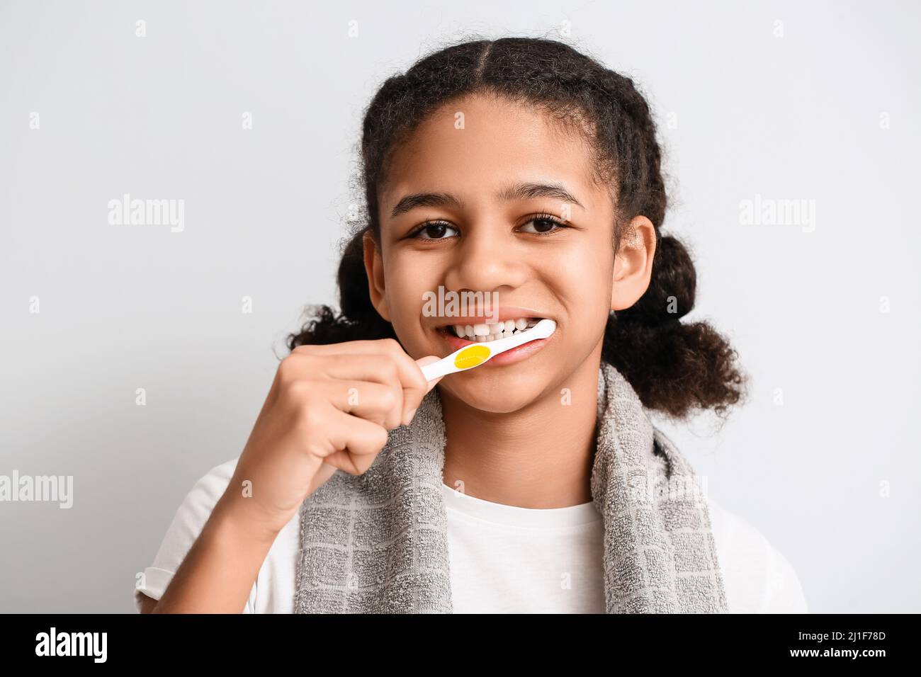 African-American teenage girl brushing teeth on light background Stock ...