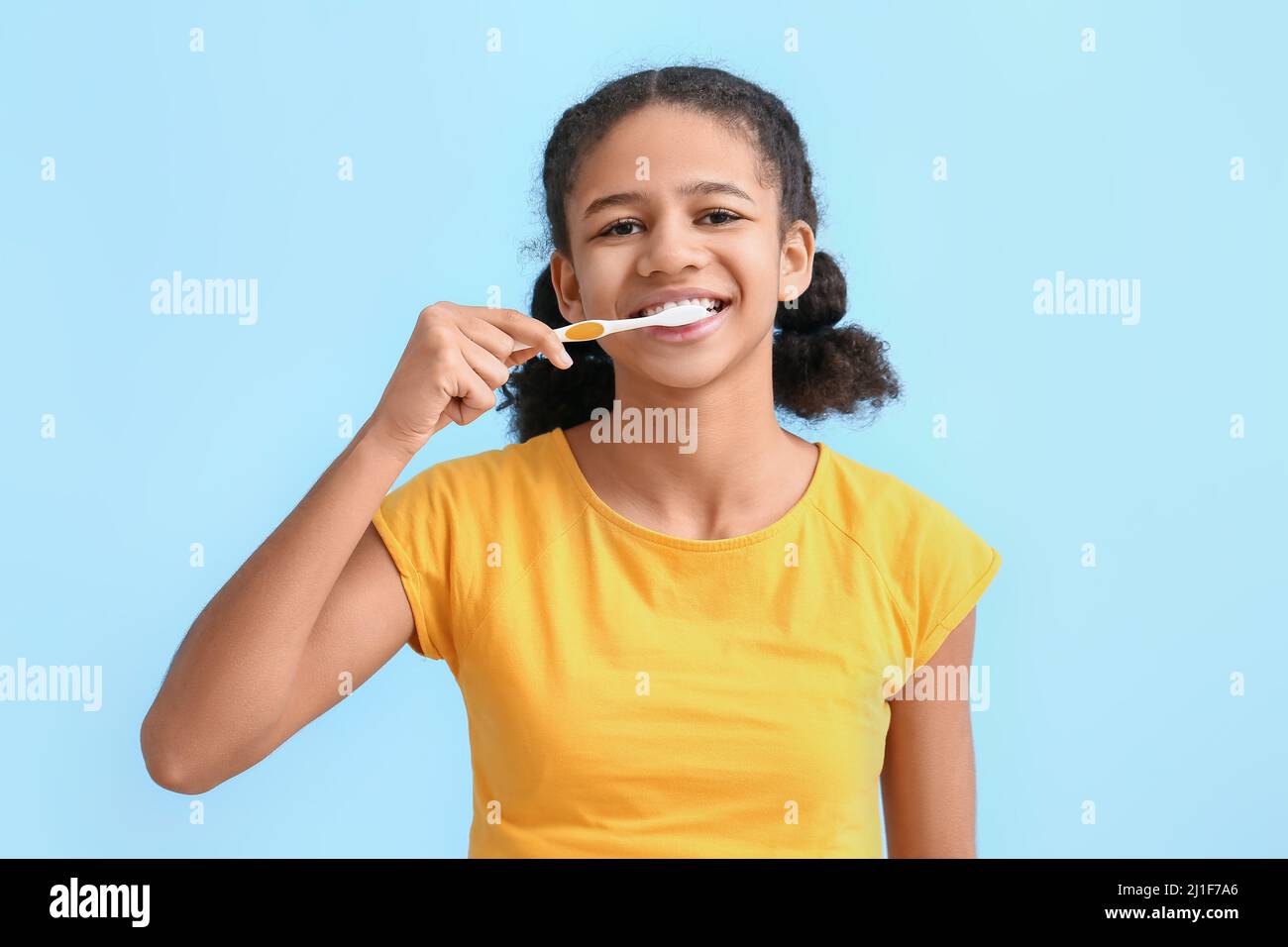 African-American teenage girl brushing teeth on blue background Stock ...