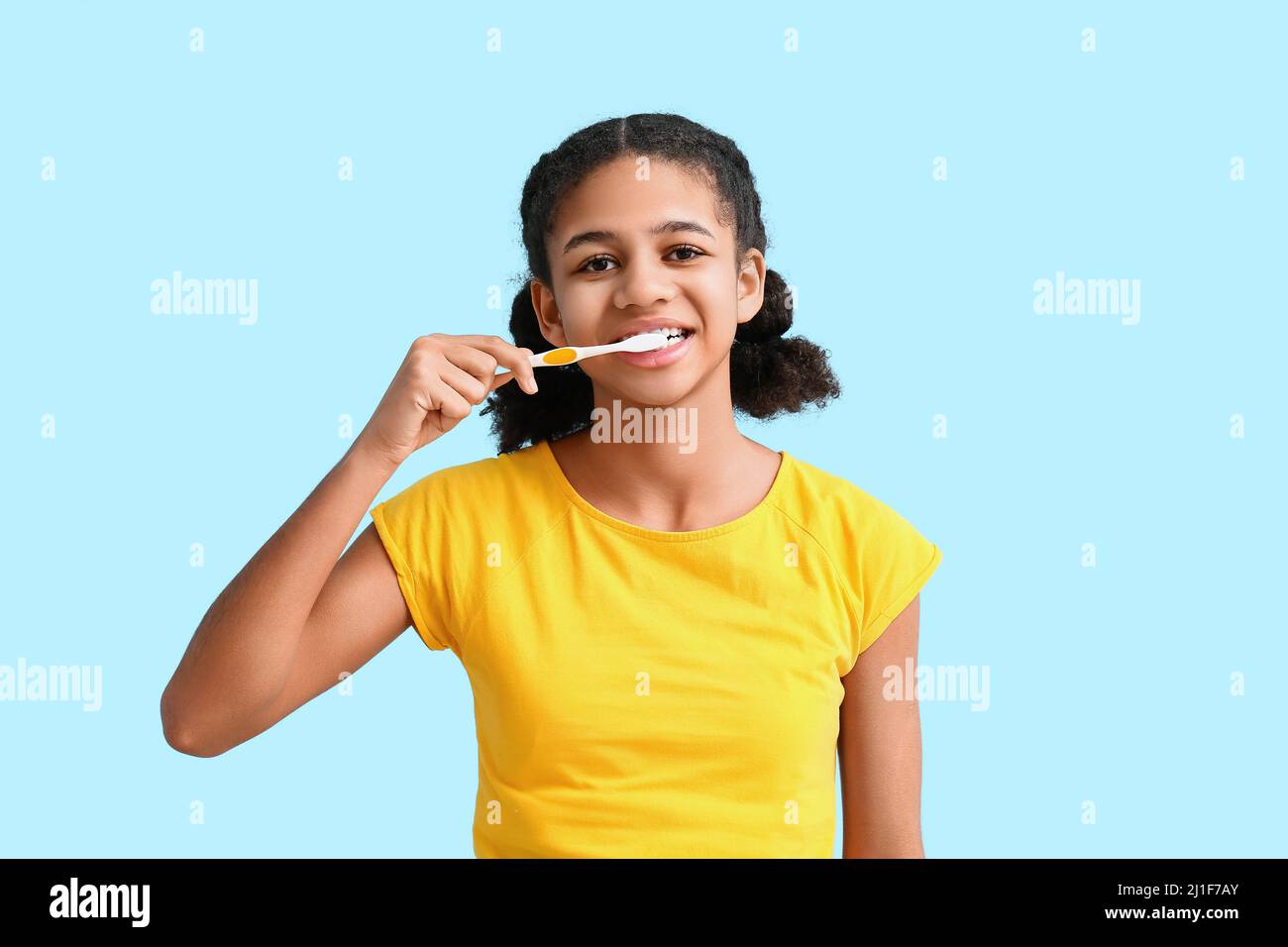African-American teenage girl brushing teeth on blue background Stock ...