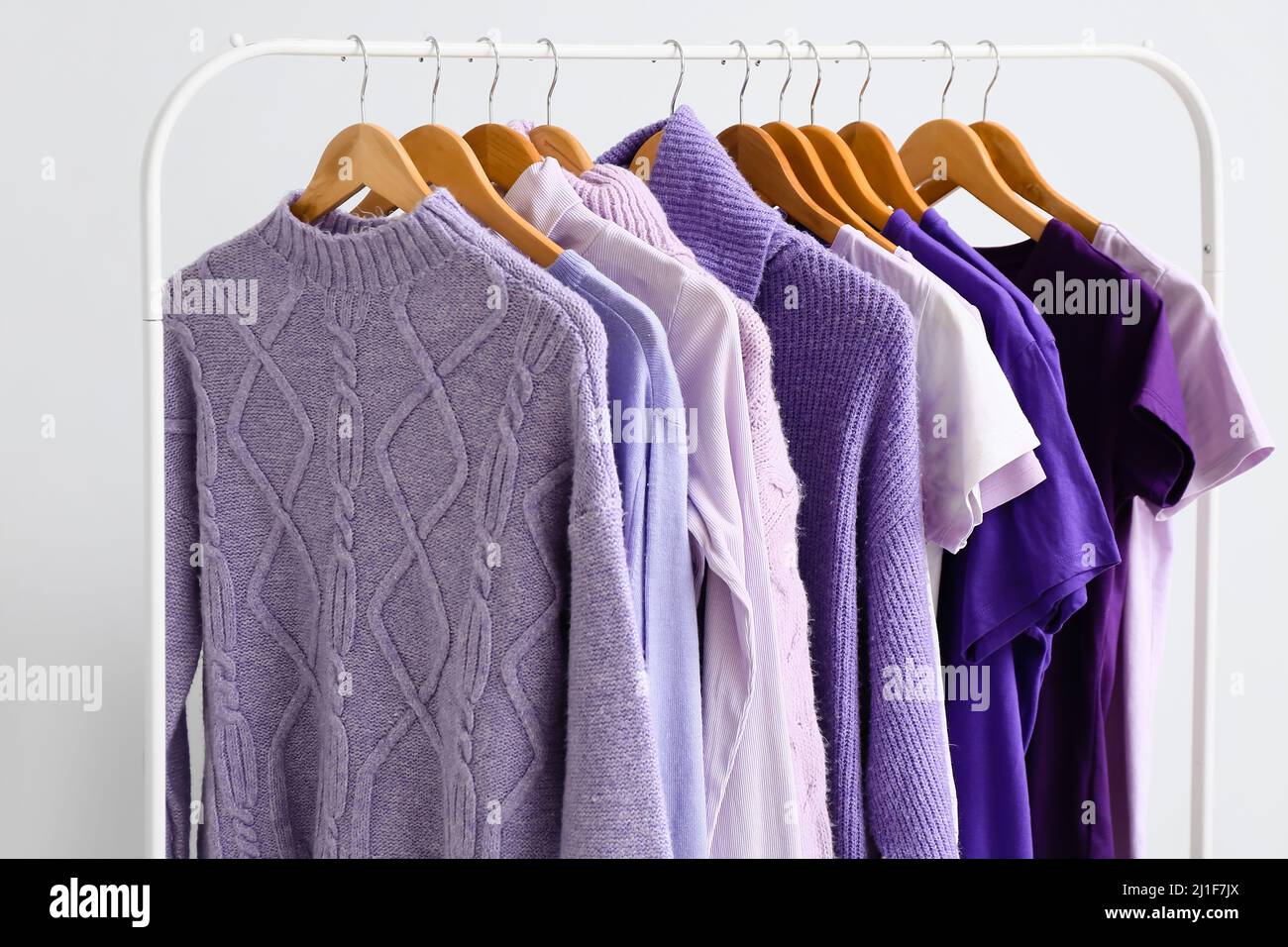 Rack with clothes in purple shades on light background, closeup Stock ...